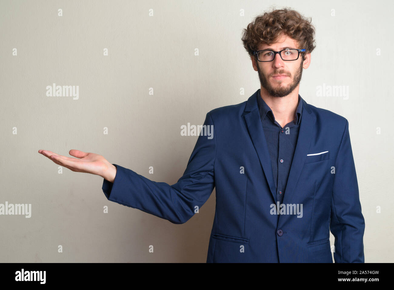 Young bearded businessman with eyeglasses in suit showing something Stock Photo - Alamy