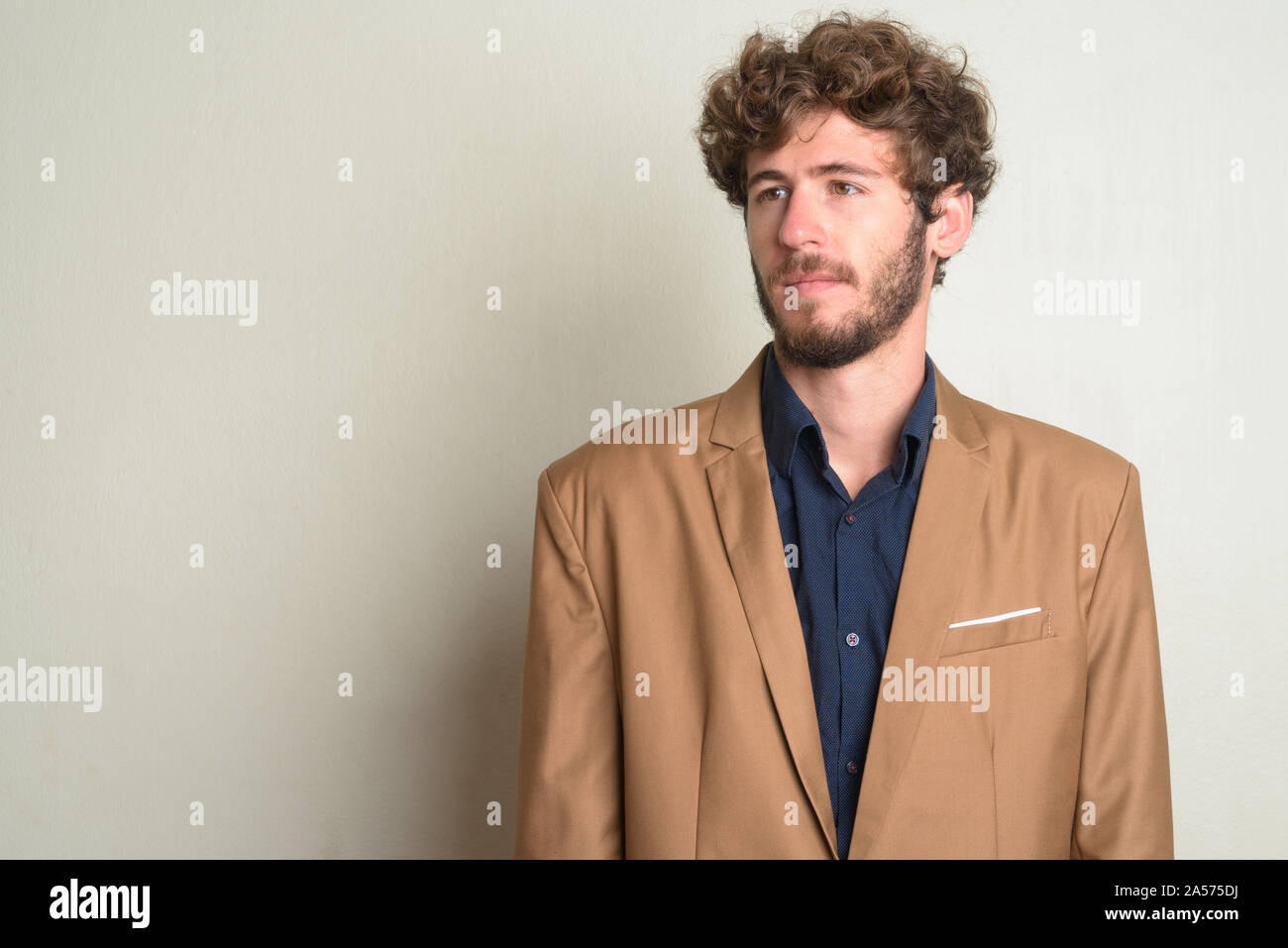 Face of young bearded businessman with curly hair in suit thinking Stock Photo - Alamy