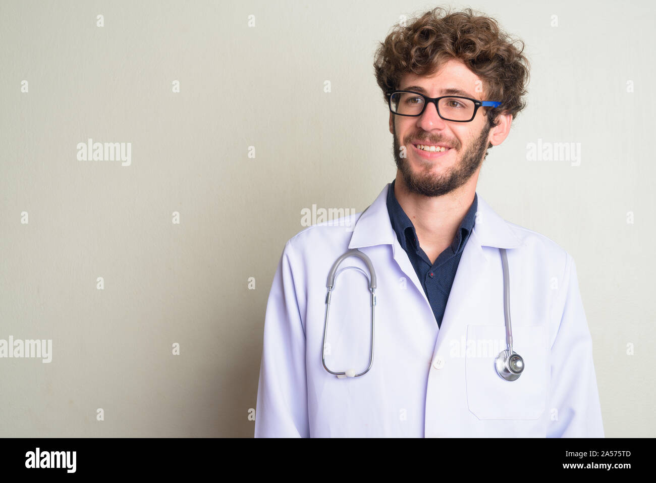 Face of happy young bearded man doctor with eyeglasses thinking Stock ...