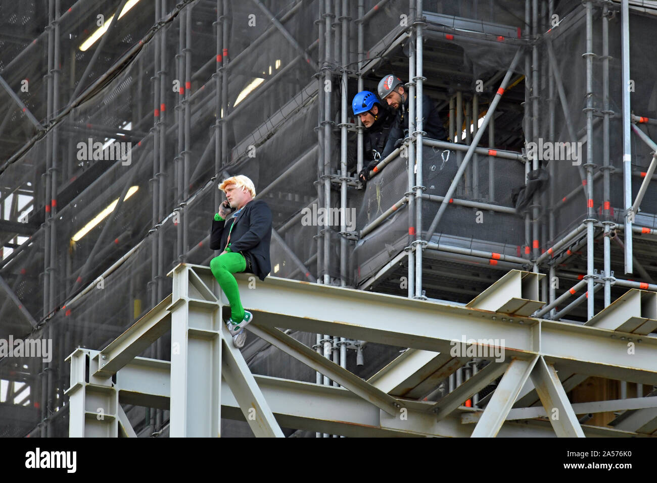 Police watch an Extinction Rebellion protester who has scaled the ...