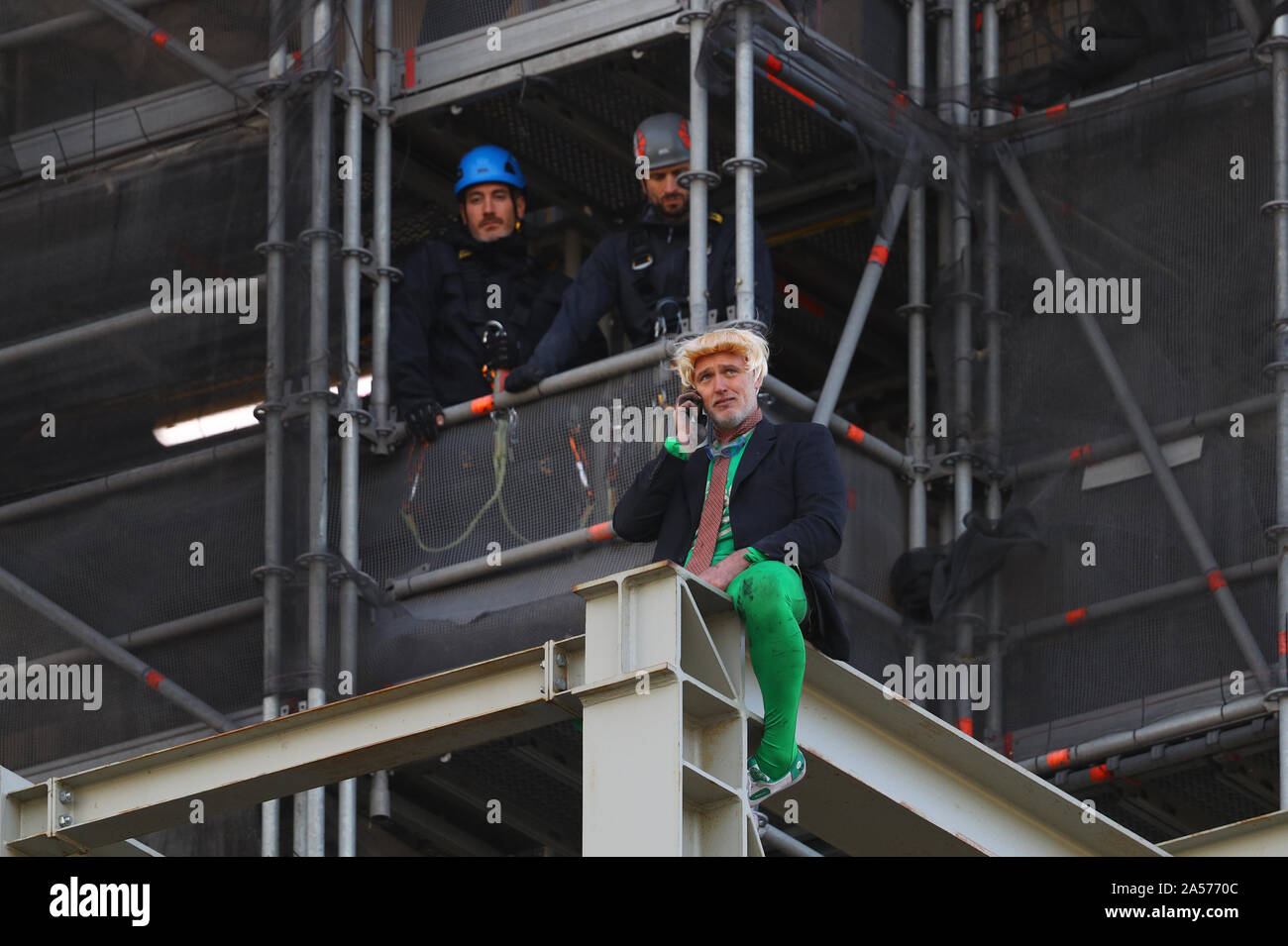 Police watch an Extinction Rebellion protester who has scaled the ...