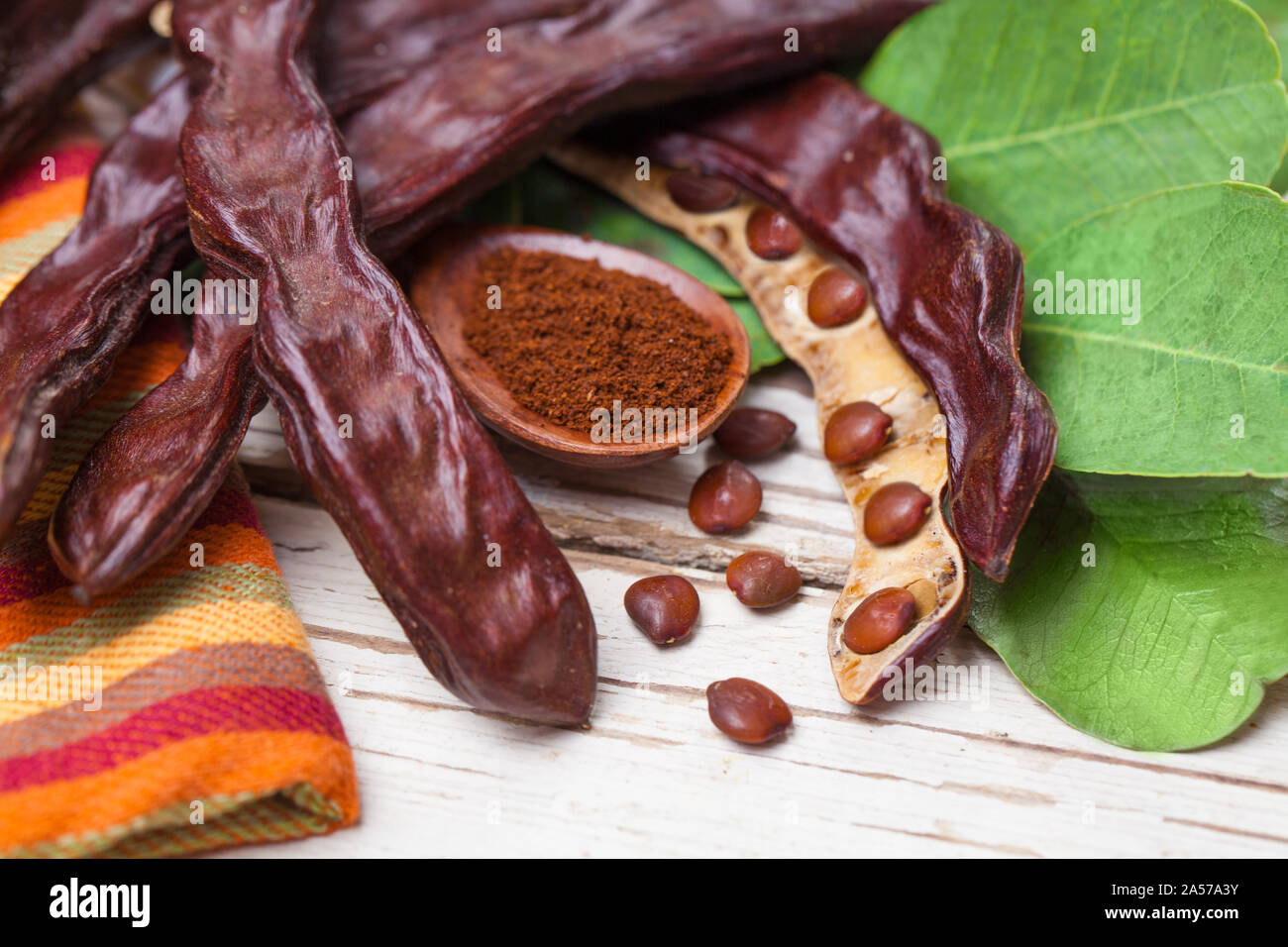 Carob with powder. Organic carob pods with seeds and leaves on white ...