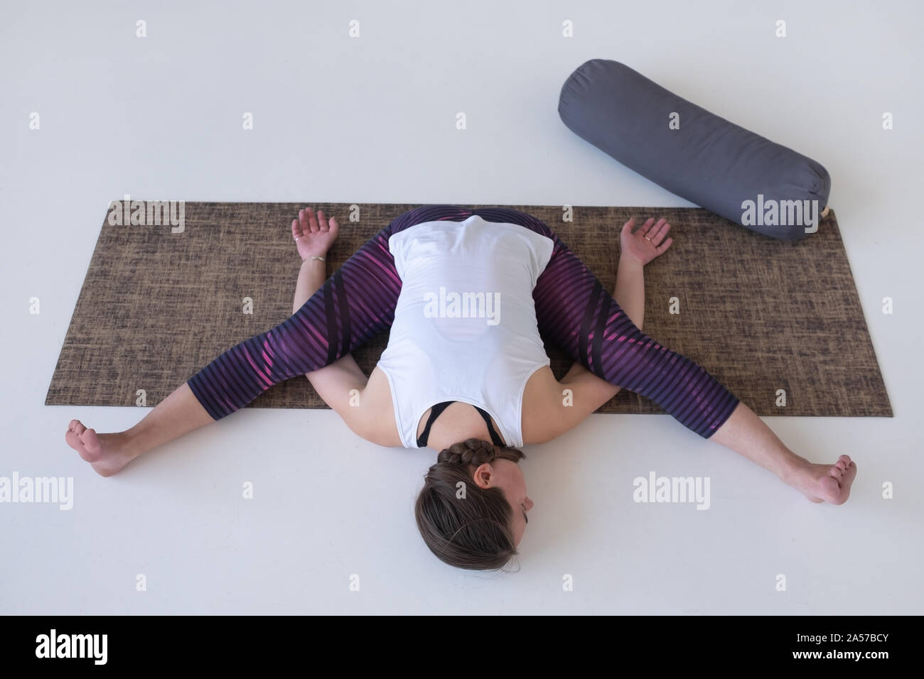 Female yoga instructor doing Tortoise Pose or Kurmasana asana exercise ...