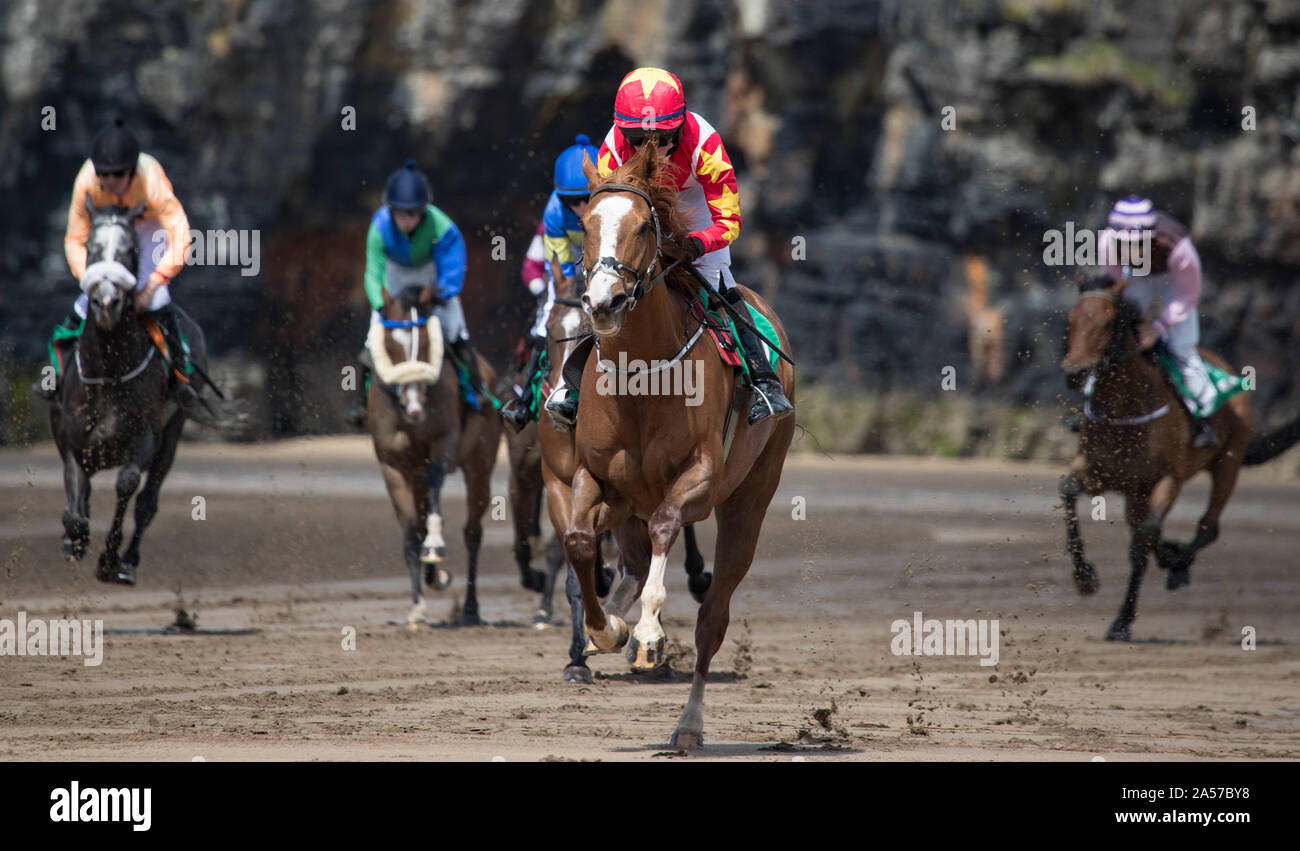 Horse racing action on the beach, focus on lead race horse and jockey ...