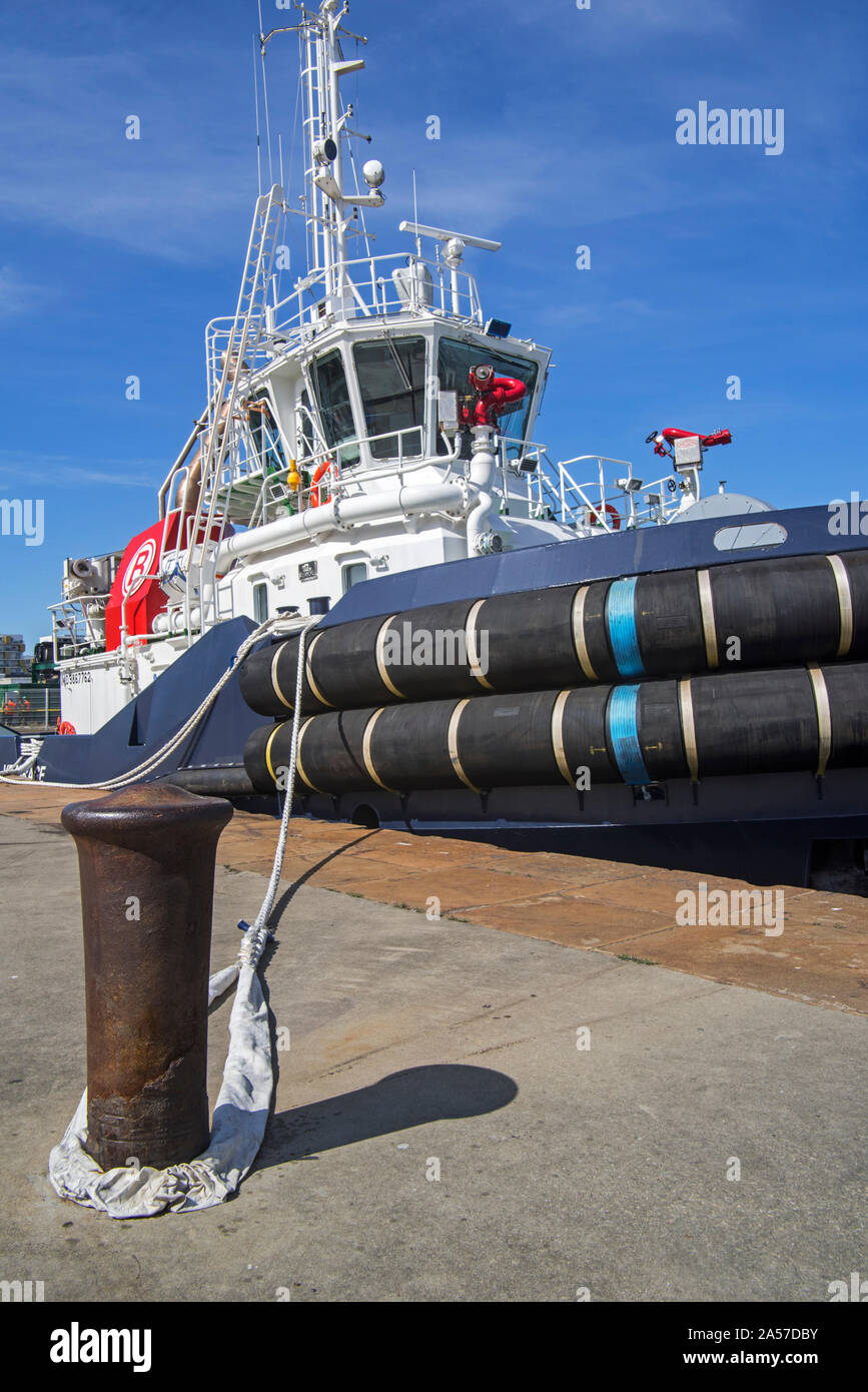 Mooring bollard and the French tug boat VB Mirage showing huge tugboat fenders docked in the ...