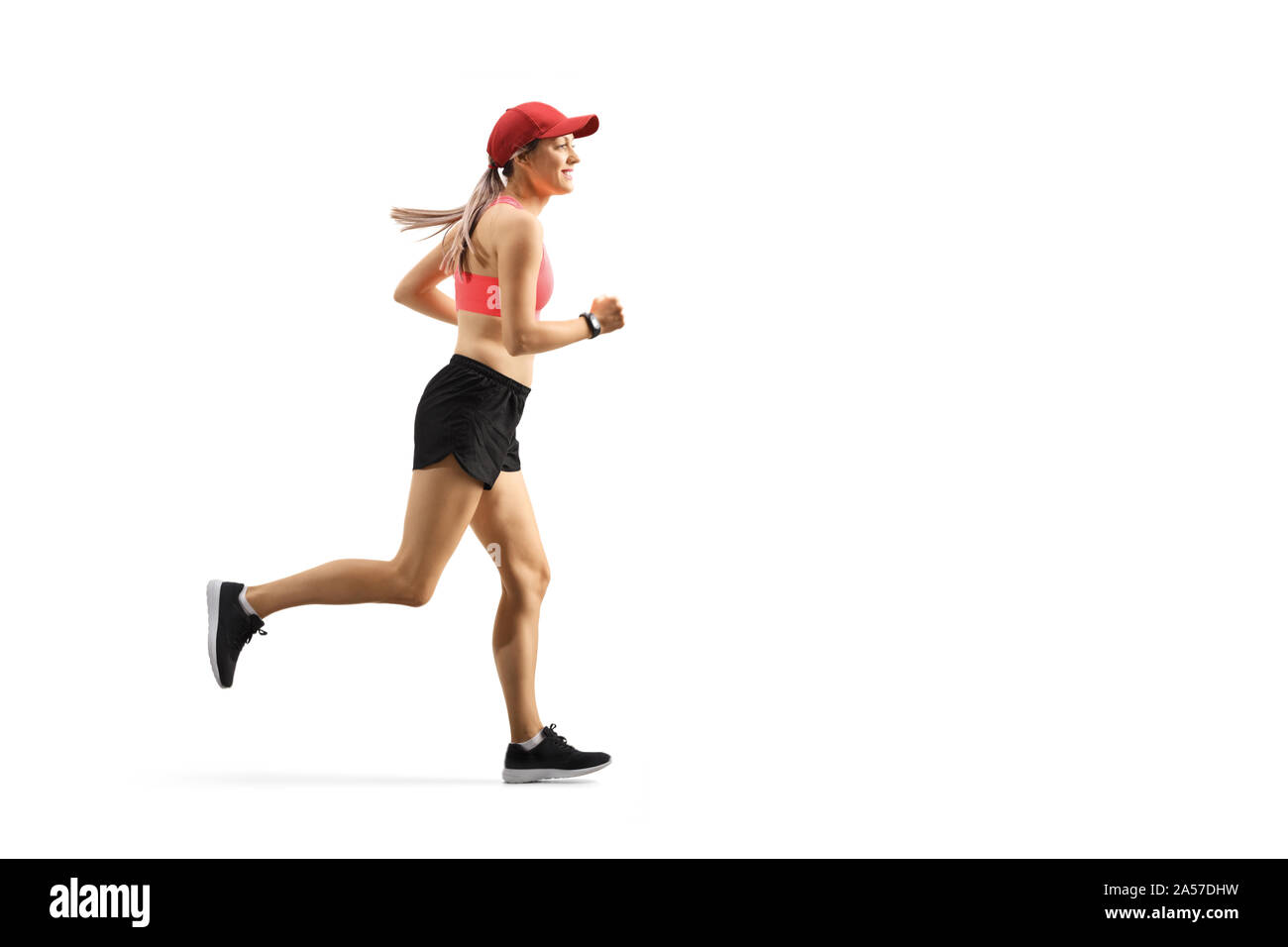 Full length profile shot of a young woman with a cap running isolated ...