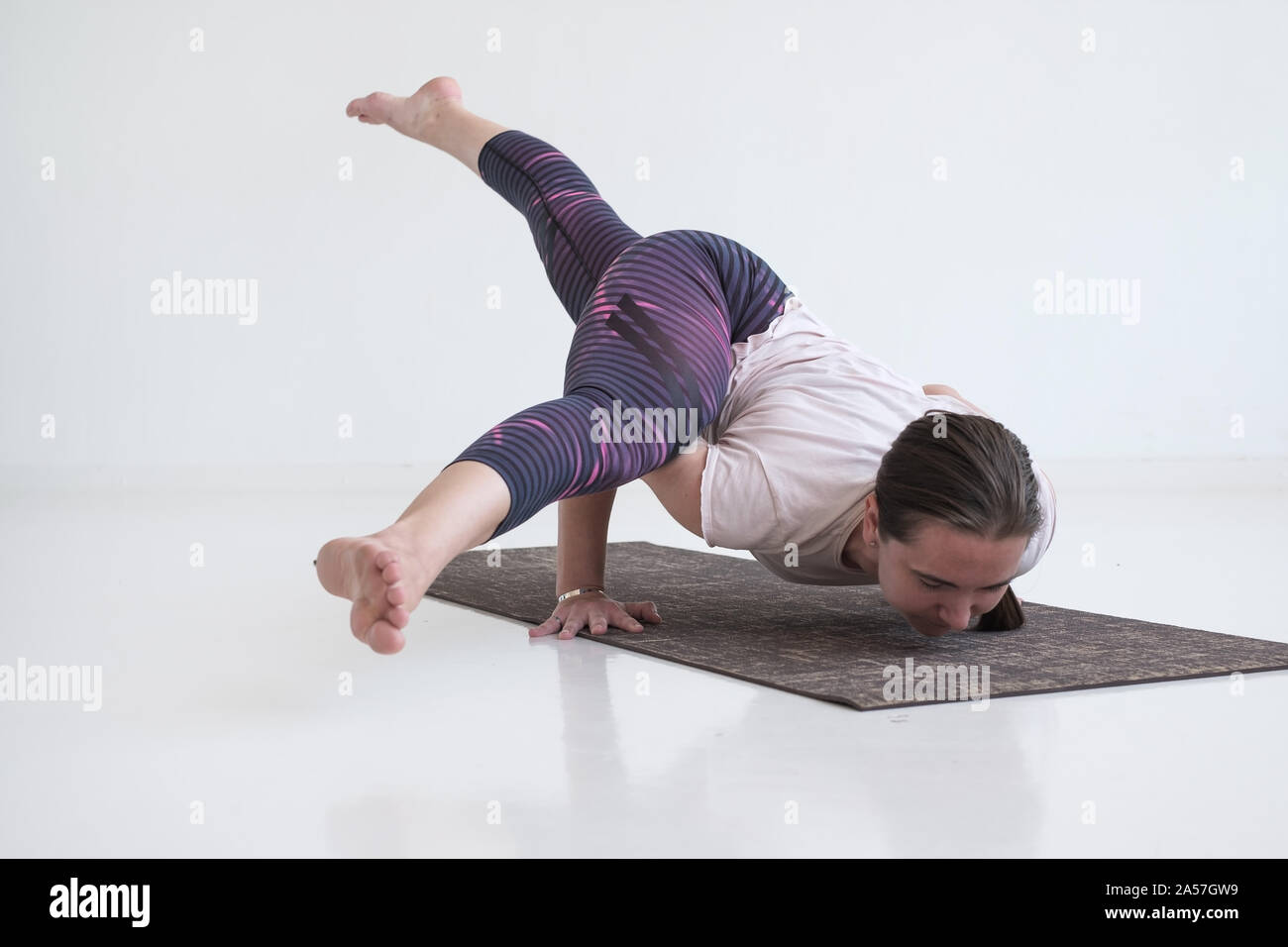 practicing yoga, doing Eka Pada Koundinyasana 2, arm balance twisted ...