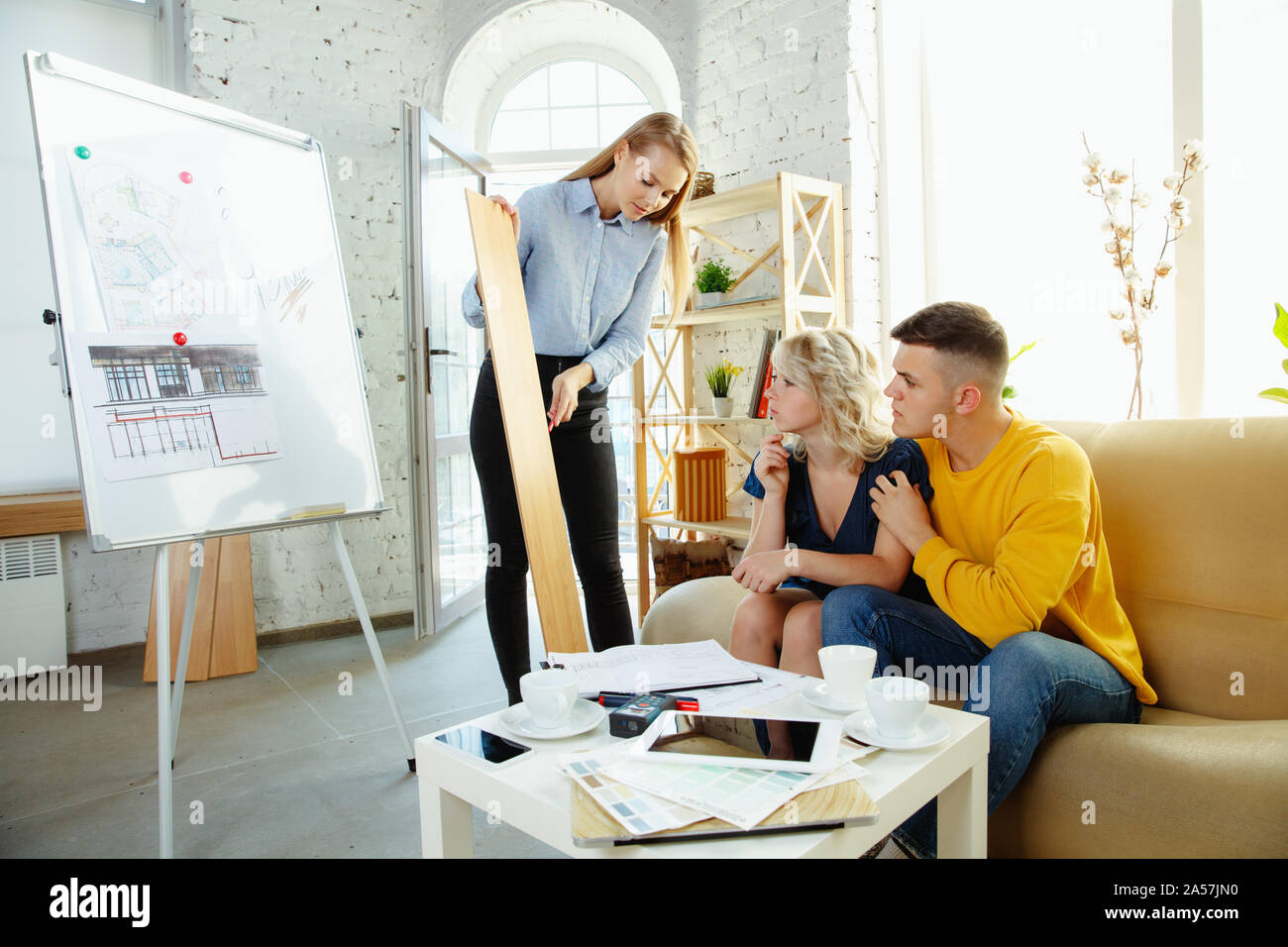 Interior designer working with young couple. Lovely family and ...