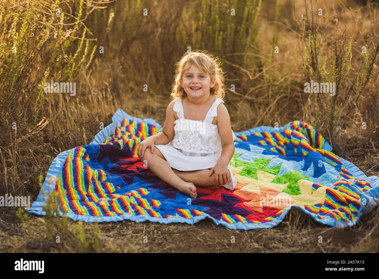 Barefoot 4 yr old girl sitting on bold blanket in nature setting Stock ...