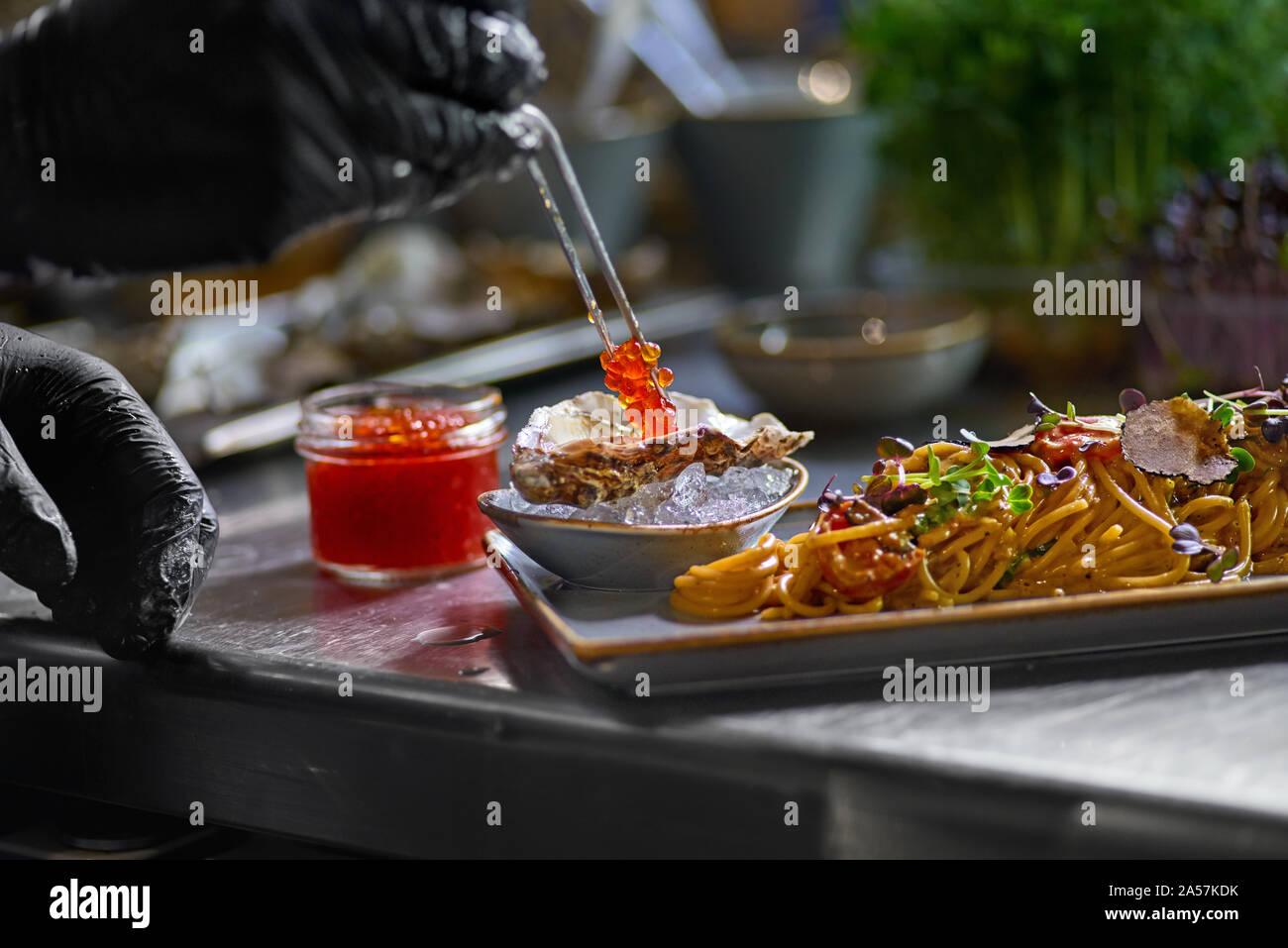 Food concept. The chef garnishes with red caviar a seafood spaghetti ...