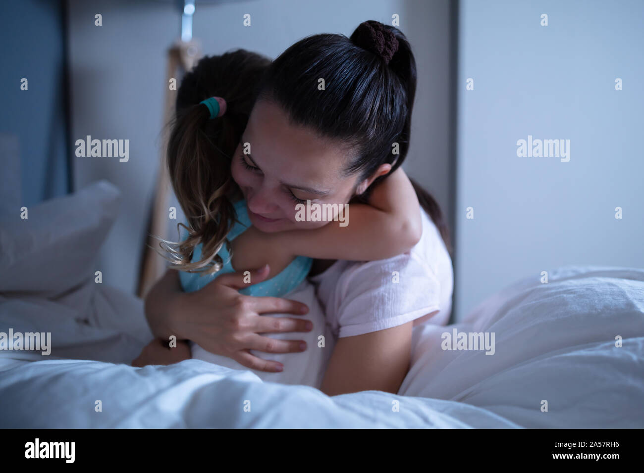 Beautiful Young Woman Hugging Her Little Daughter On Bed Stock Photo ...