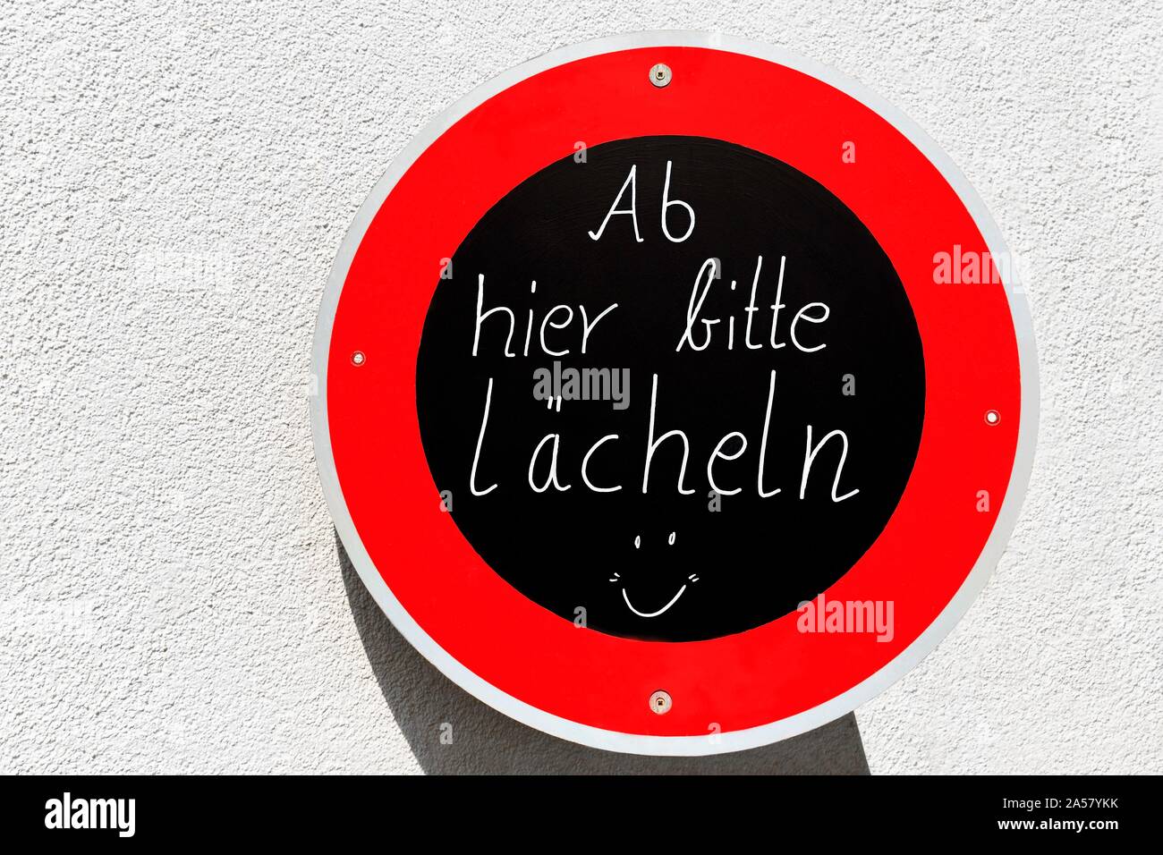 Traffic sign with inscription From here please smile and smiley, hangs ...