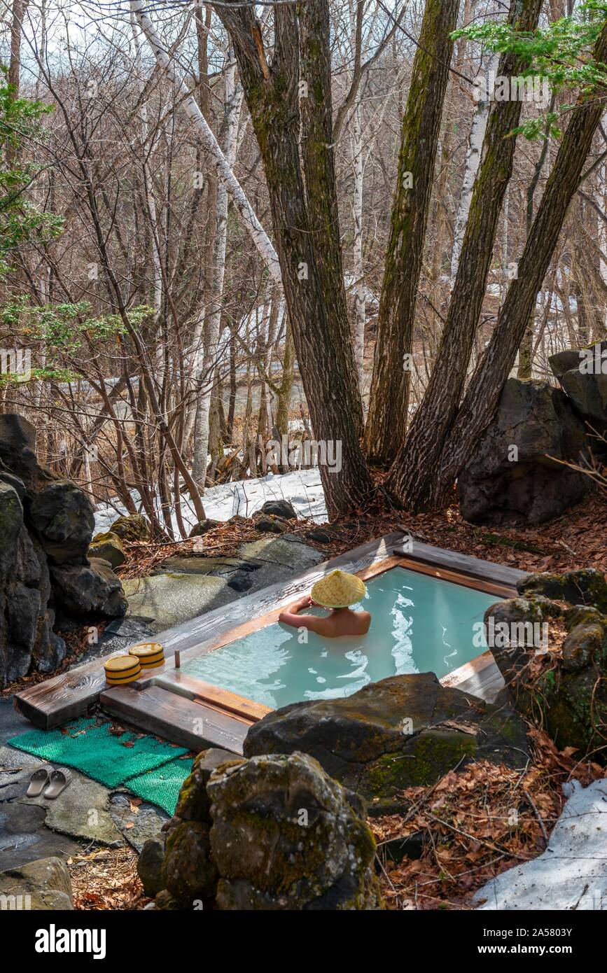 Woman bathing in an onsen, hot thermal spring of a guesthouse ...