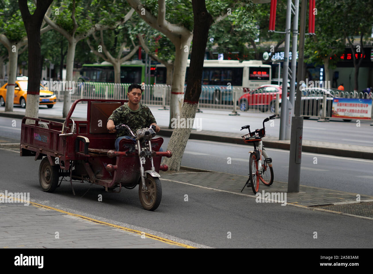 Man riding a tricycle moped with cargo space over the road Stock Photo ...