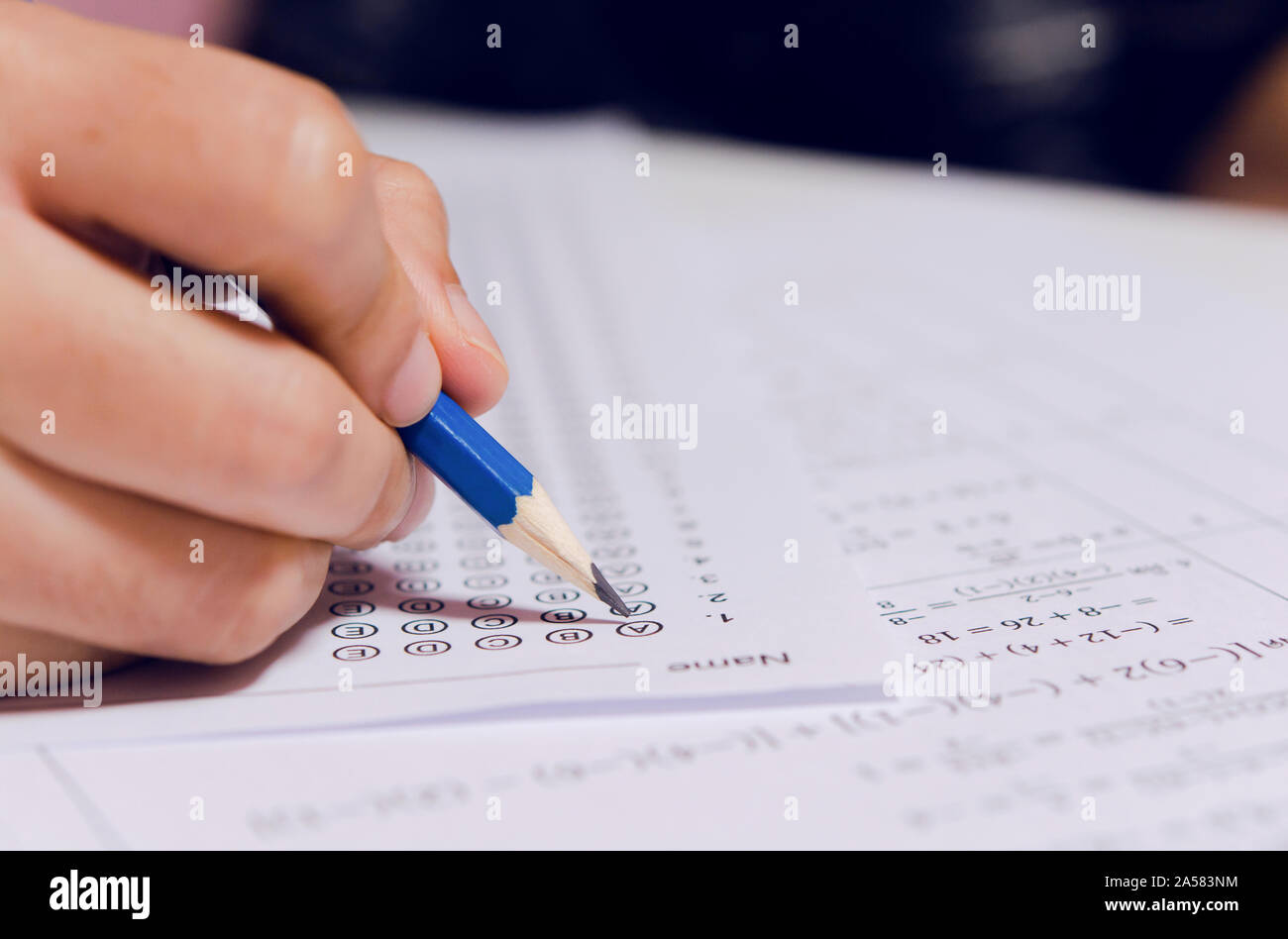 Students hand holding pencil writing selected choice on answer sheets ...