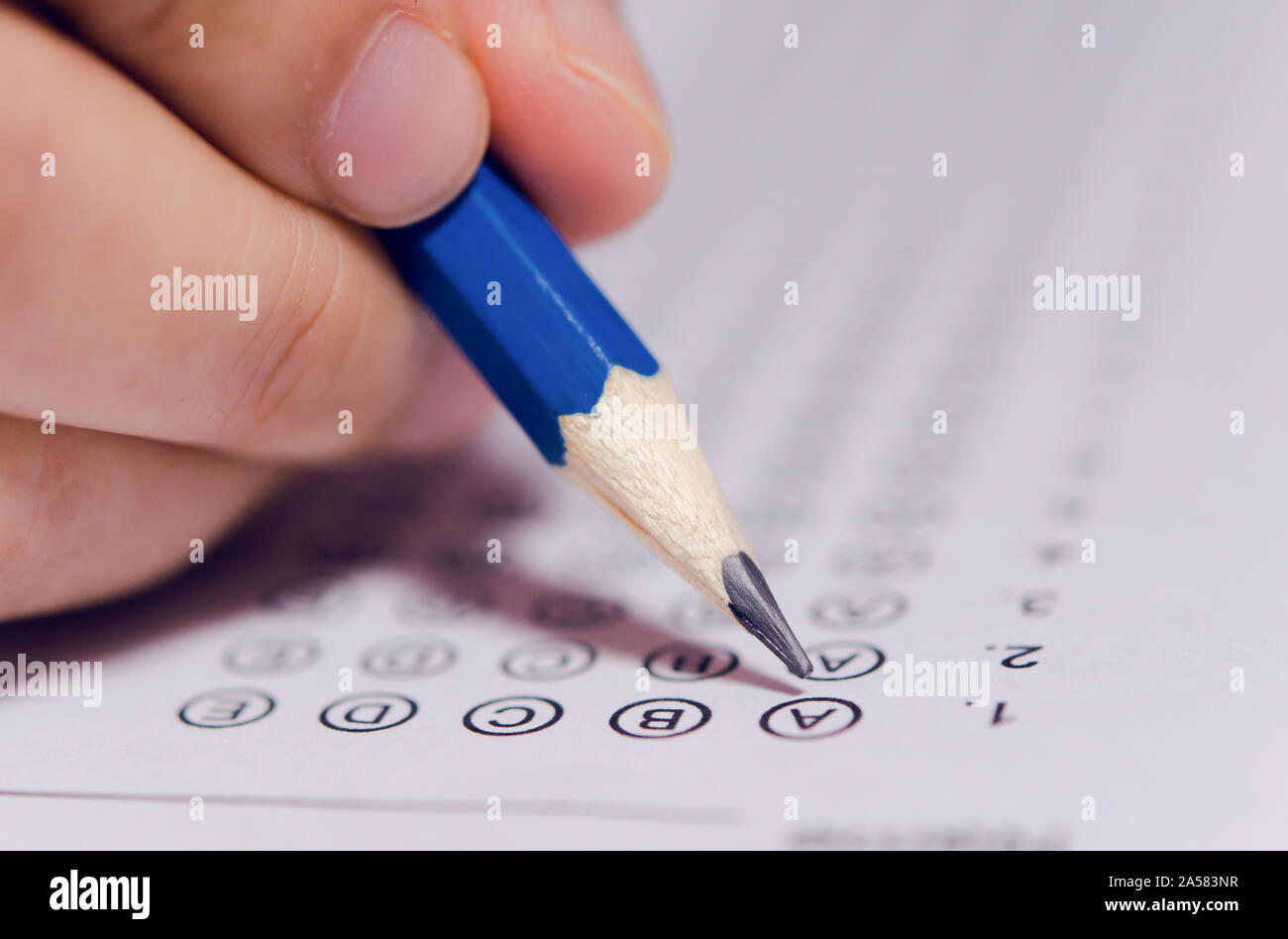 Students hand holding pencil writing selected choice on answer sheets ...