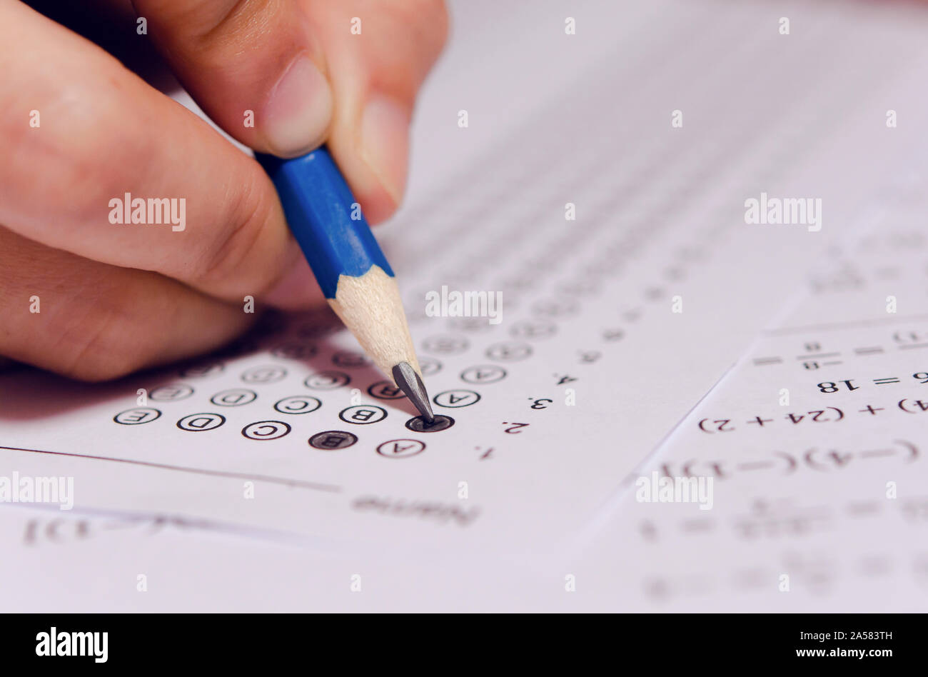 Students hand holding pencil writing selected choice on answer sheets ...