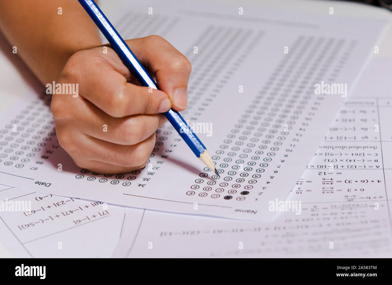 Students hand holding pencil writing selected choice on answer sheets ...