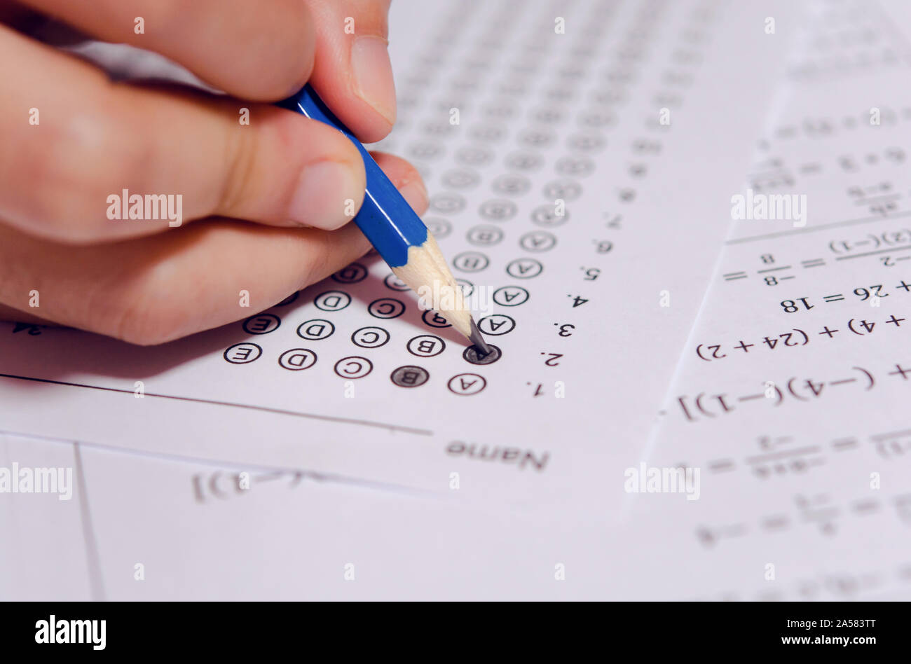 Students hand holding pencil writing selected choice on answer sheets ...