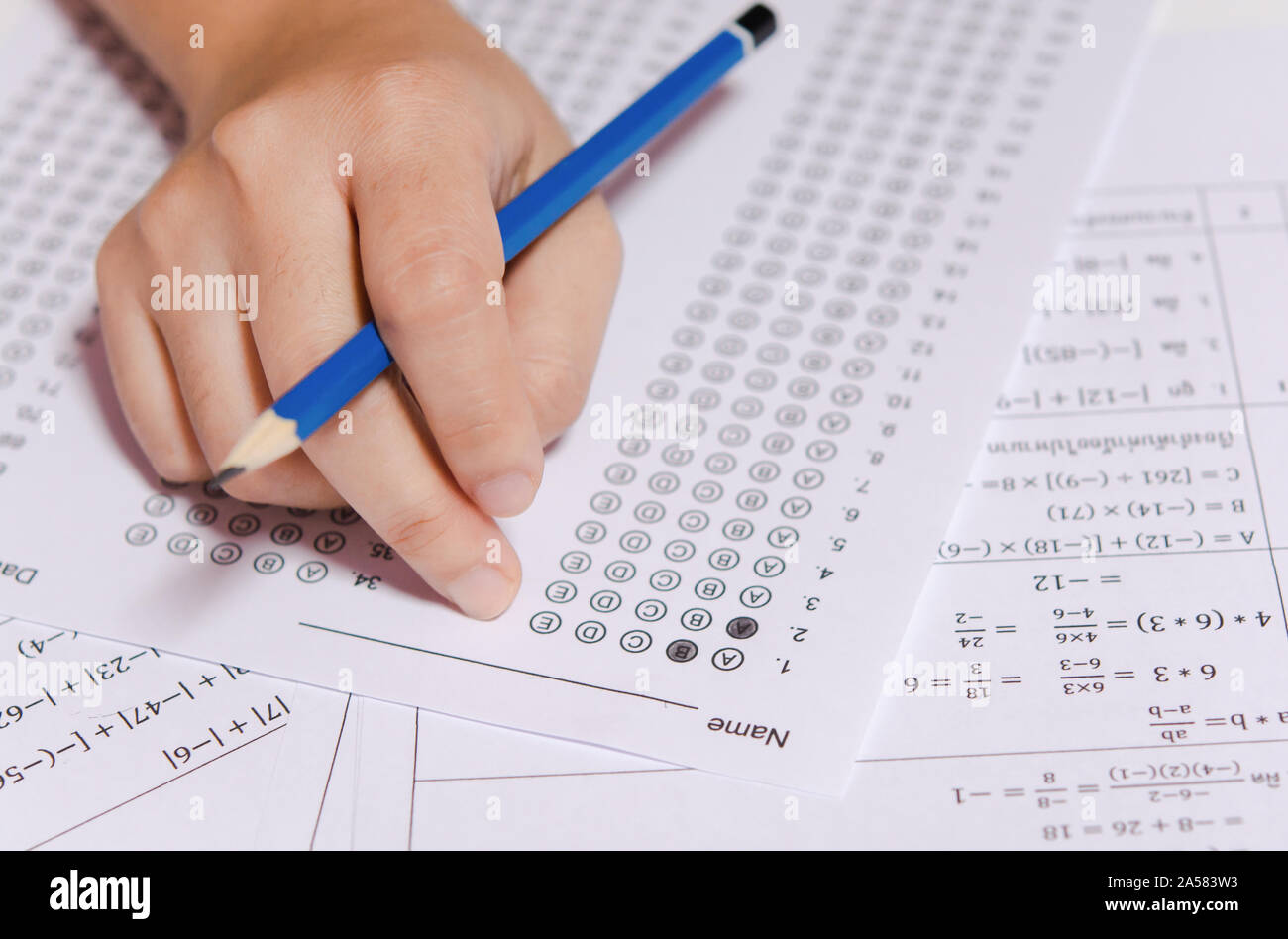 Students hand holding pencil writing selected choice on answer sheets ...