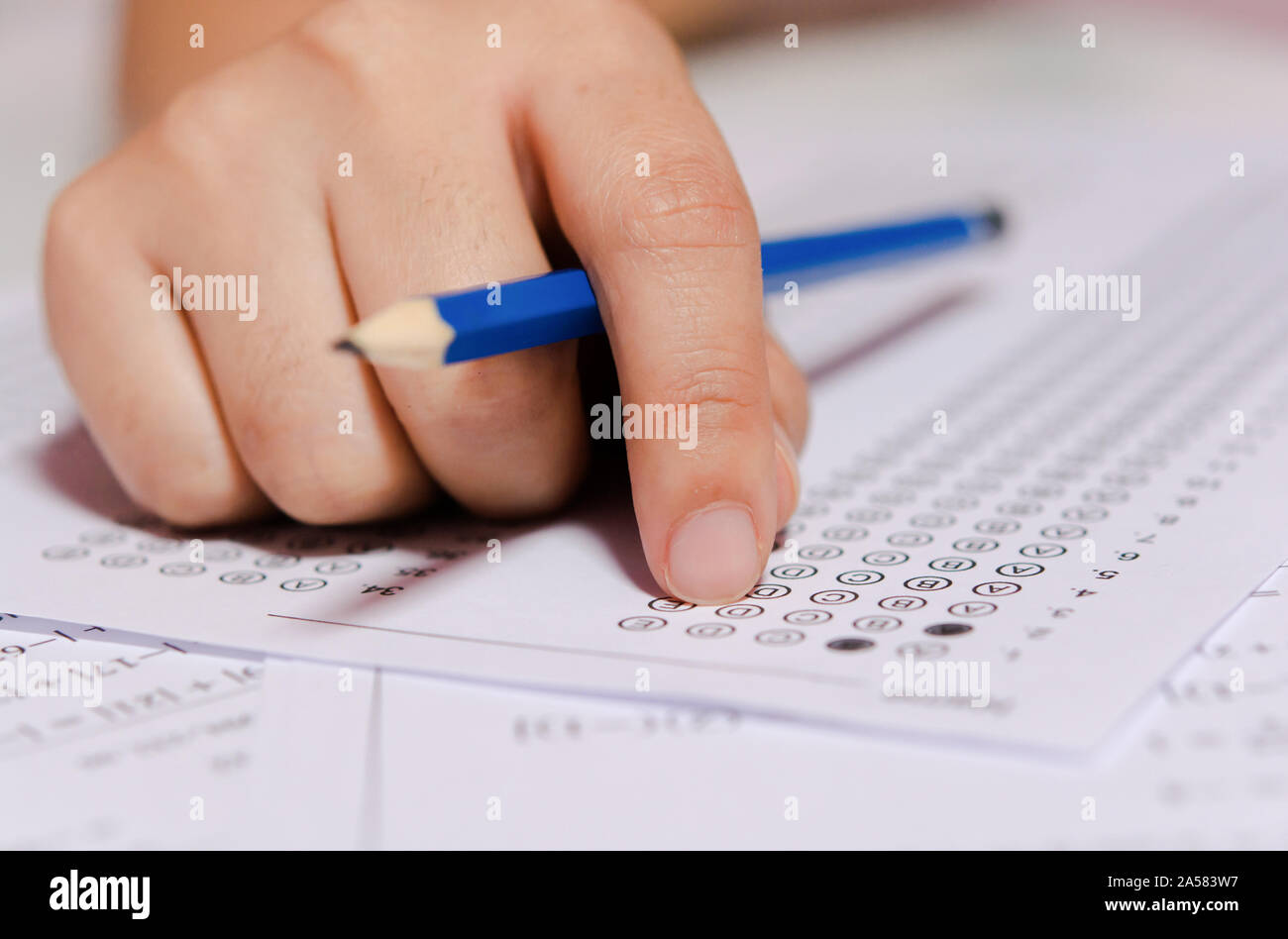 Students hand holding pencil writing selected choice on answer sheets ...