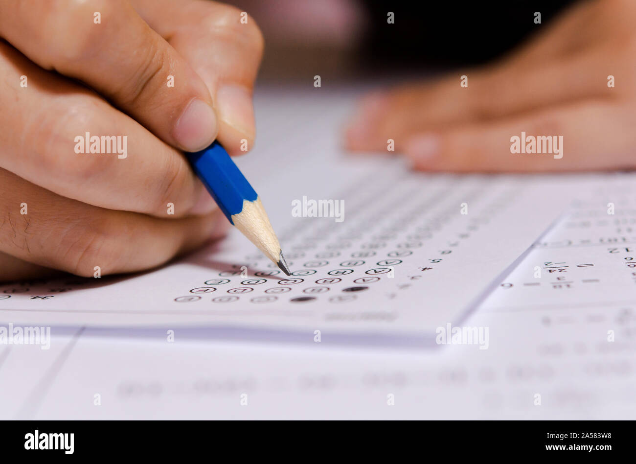 Students hand holding pencil writing selected choice on answer sheets ...