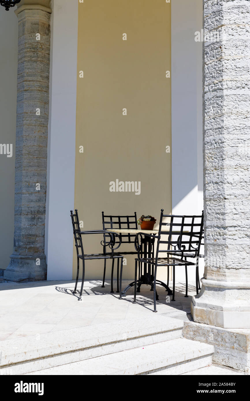 Cafe chairs and table against a building wall behind pillar Stock Photo ...