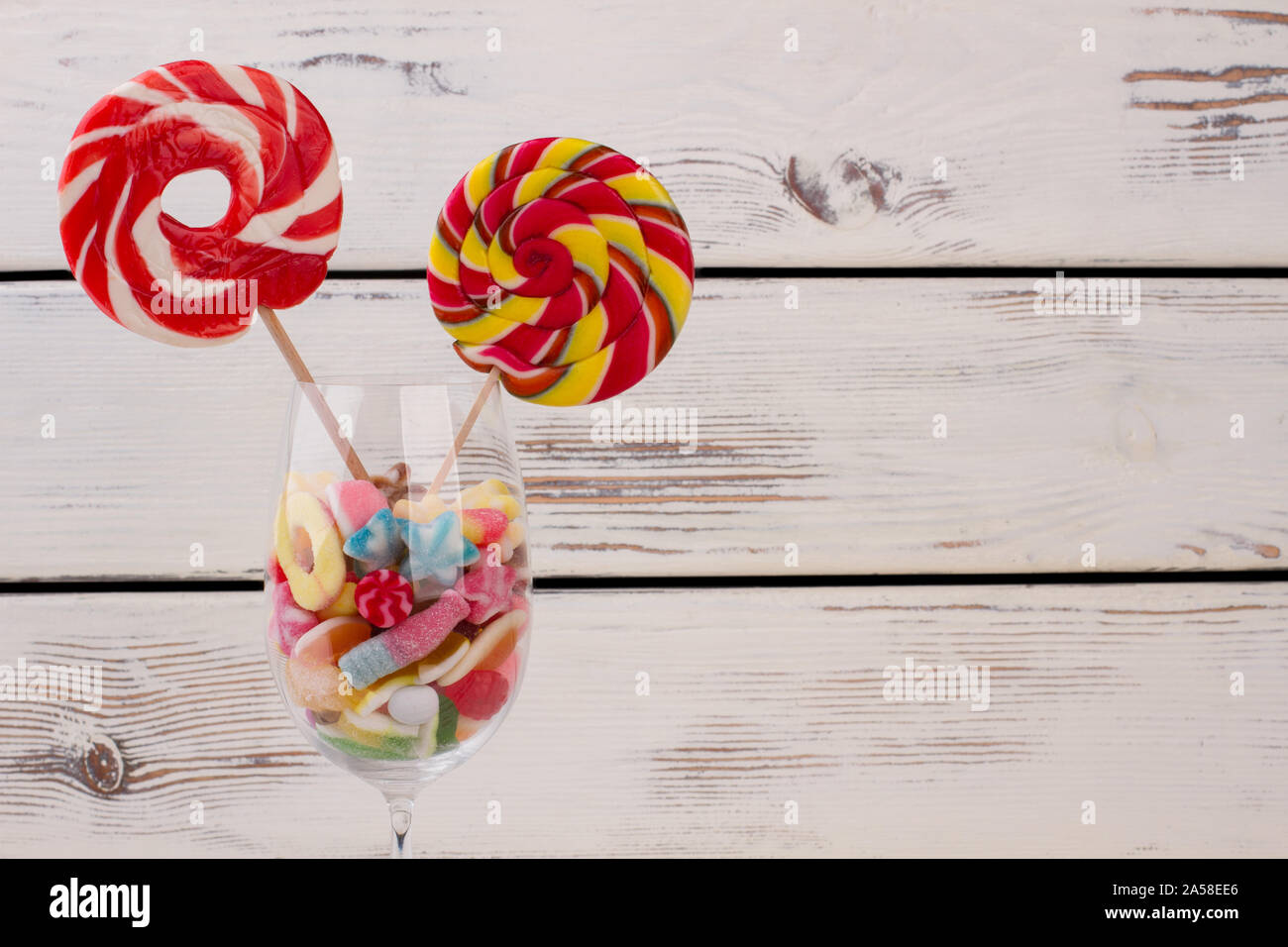 Two spiral lollipops and candies in wine glass Stock Photo - Alamy