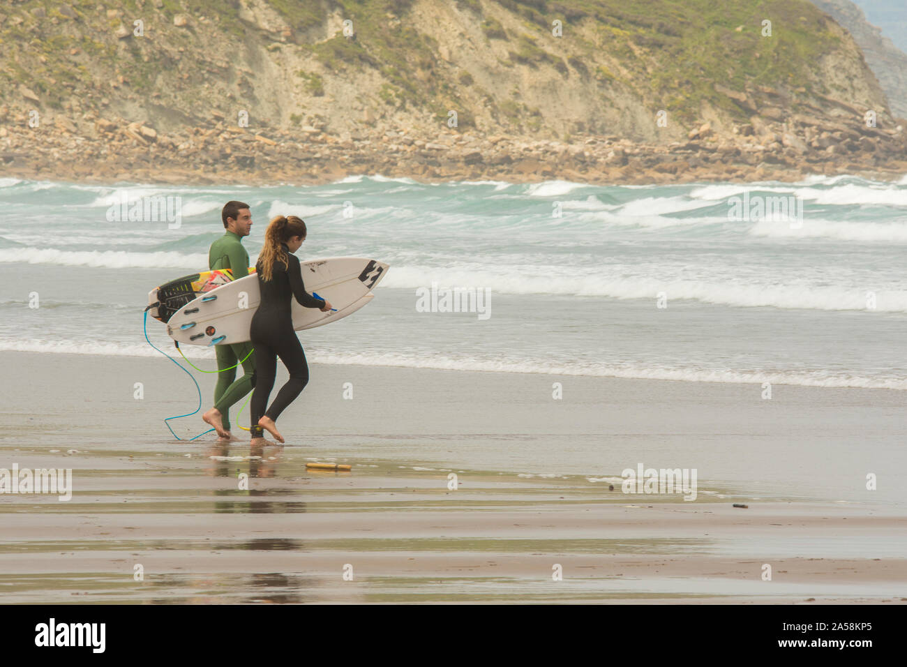 Surfers walking in the beach in basque country Stock Photo - Alamy