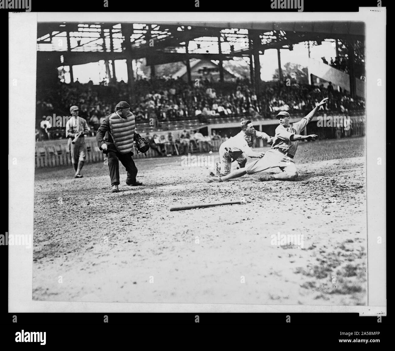 Umpire makes the call as the catcher applies tag to ball player sliding ...