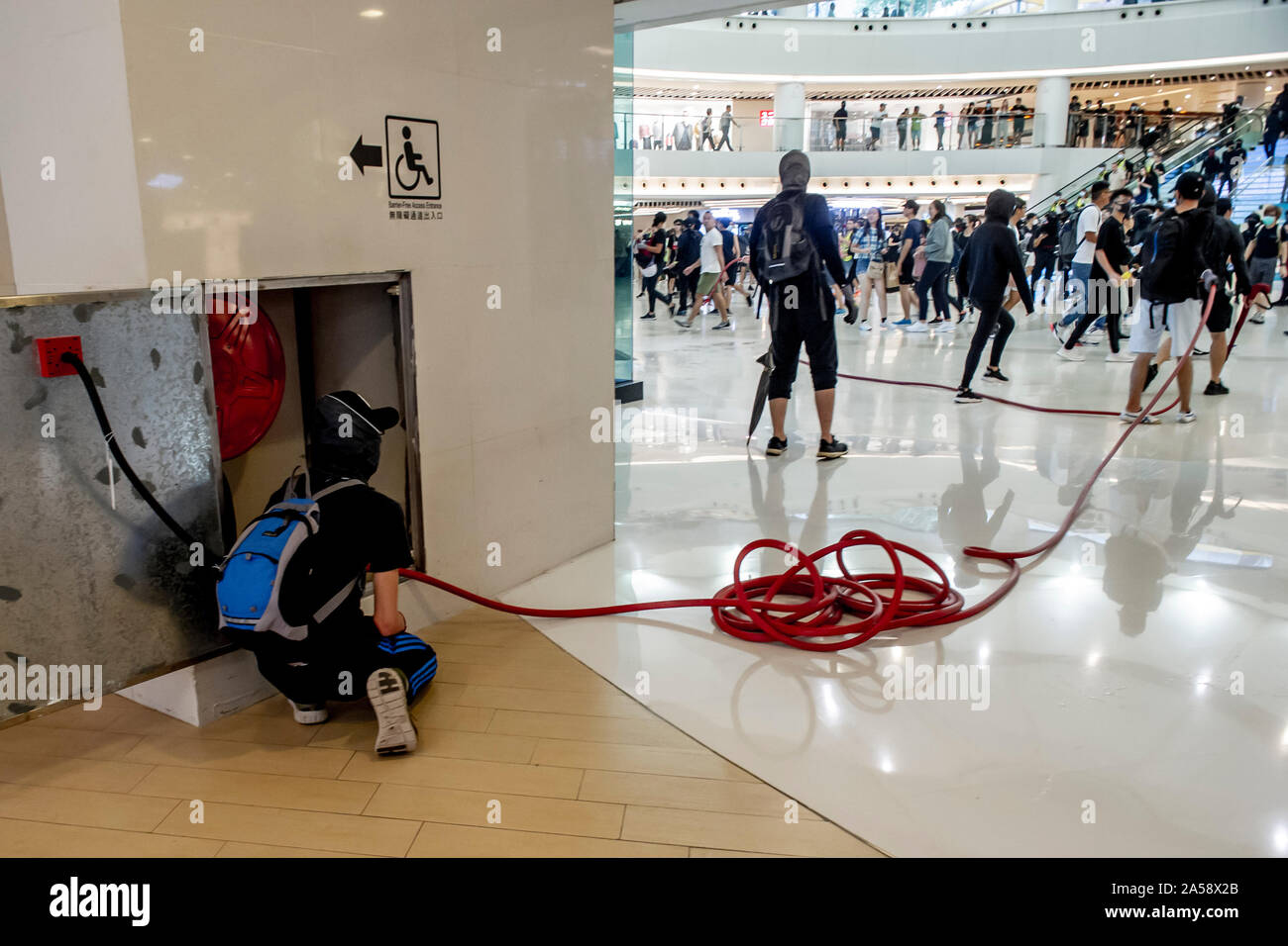Hong Kong protestors, having prised open a cupboard with a fire hose ...