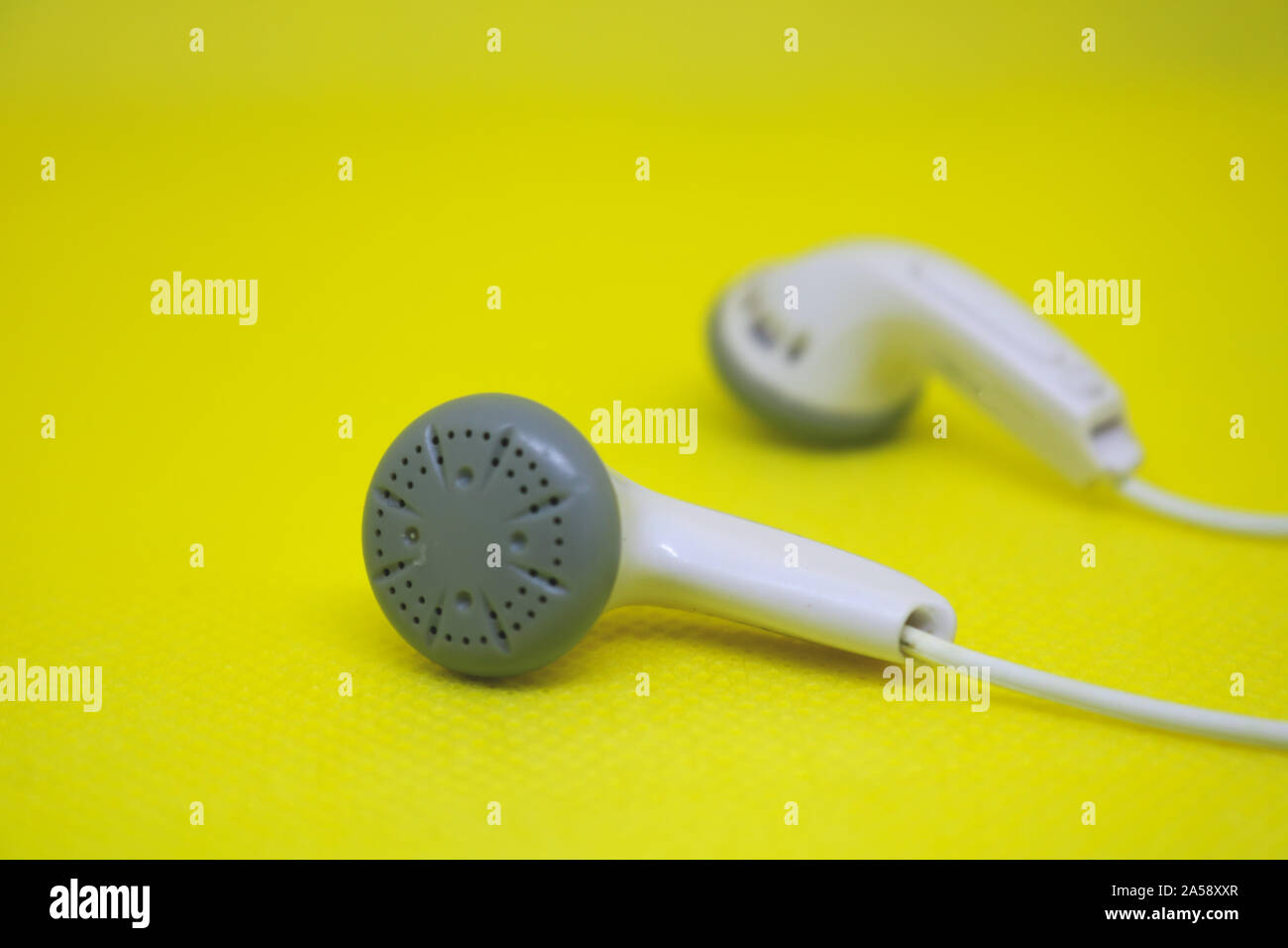 white earphones with yellow background Stock Photo - Alamy