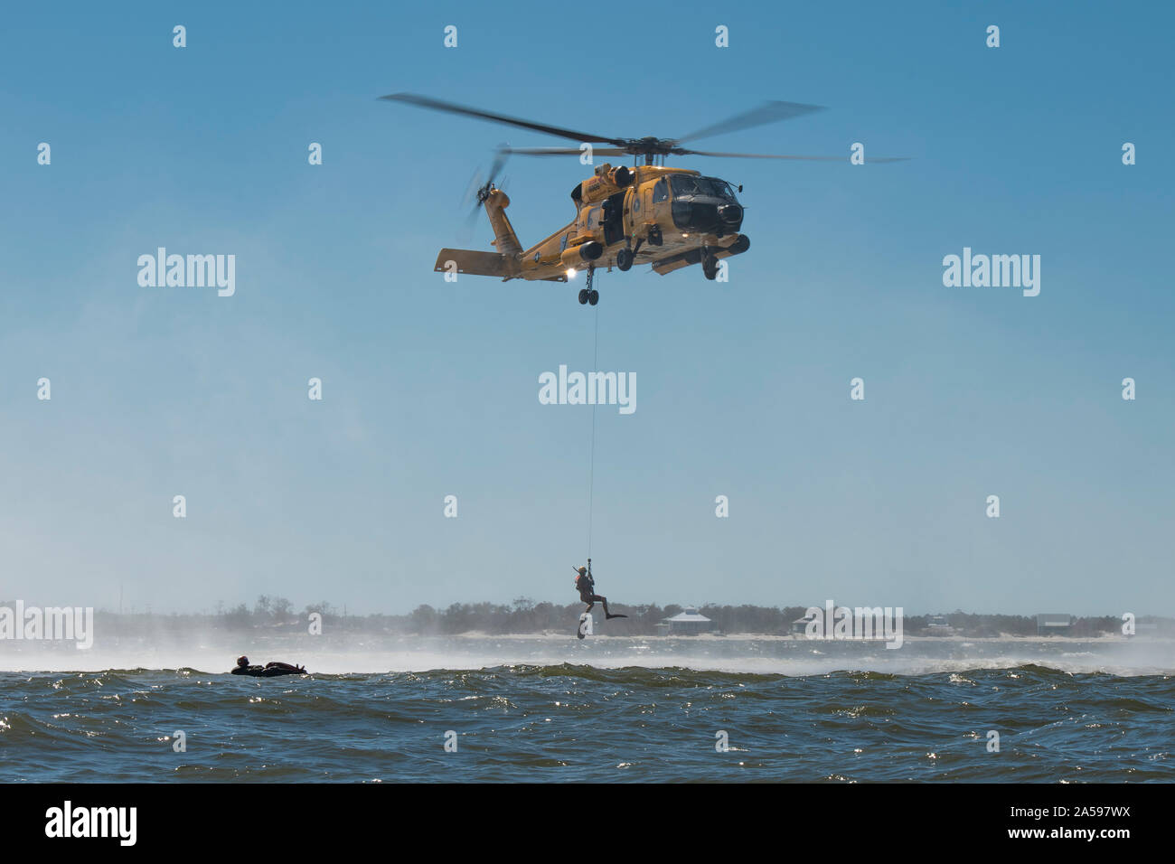 A U.S. Coast Guard rescue swimmer descends into water to save a downed ...