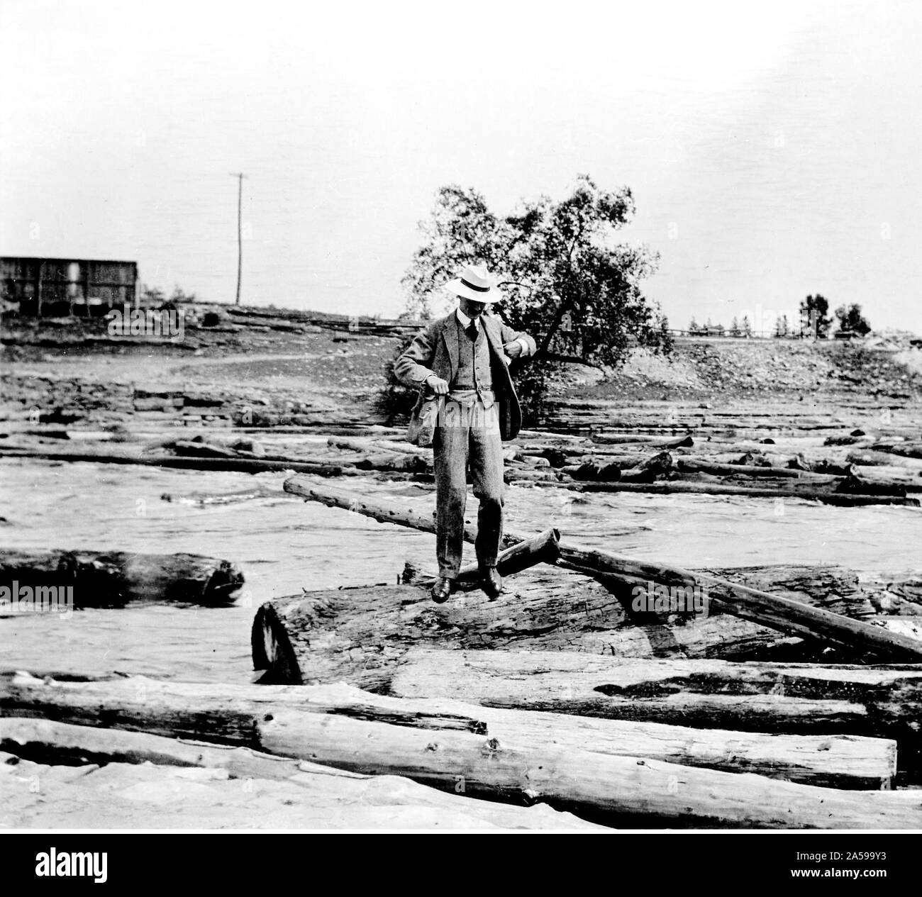 Man standing on floating logs in the Moira River, Ontario. Photograph ...
