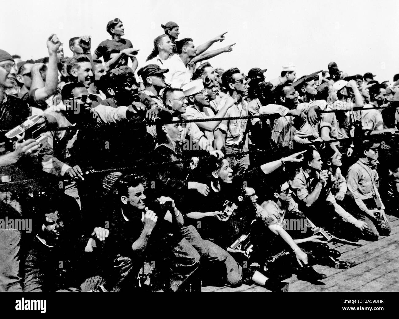 Crew members of the U.S. Navy Carrier Champlain cheer and take pictures ...