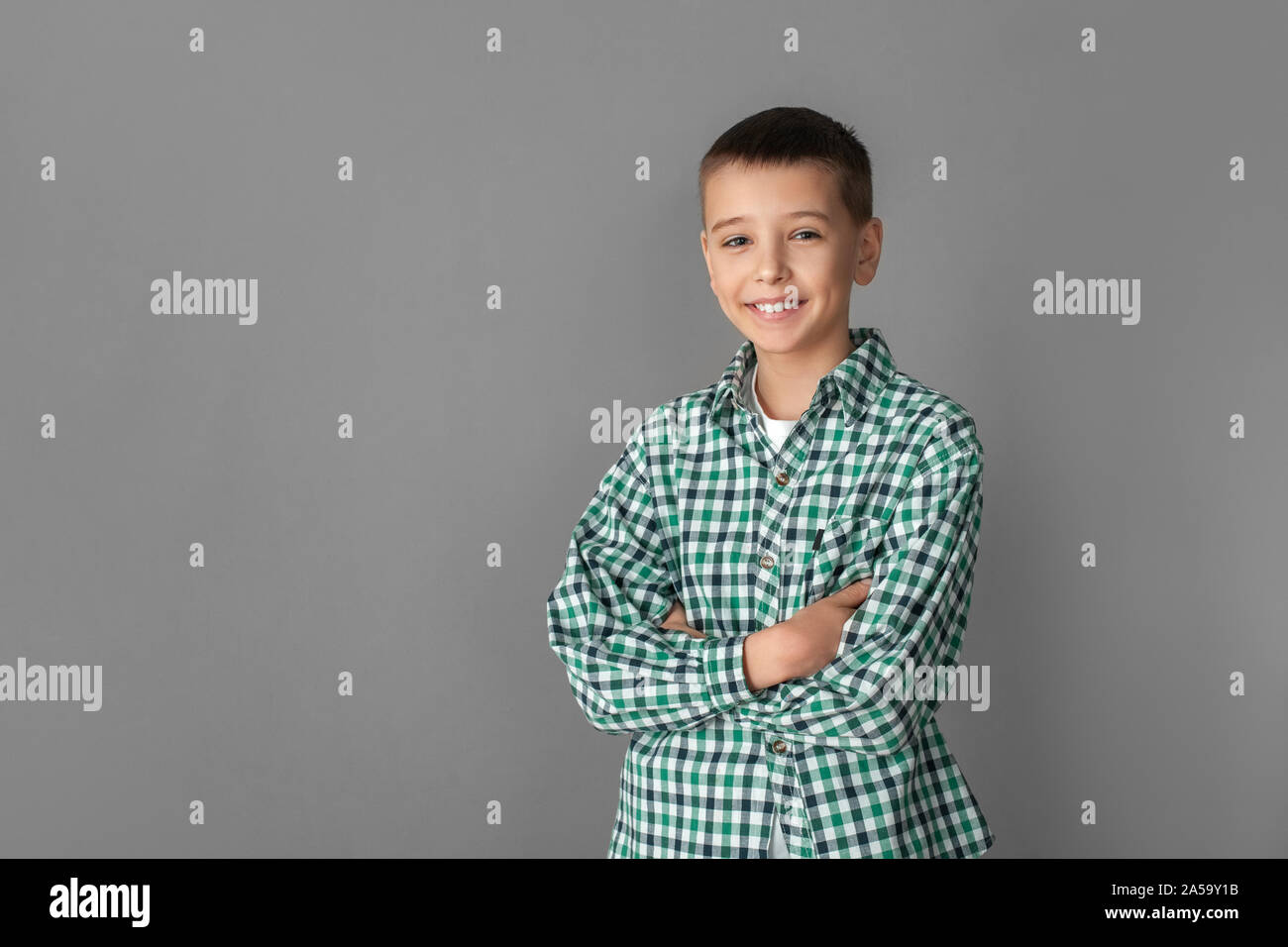 Freestyle. Boy standing isolated on grey wall crossed arms smiling ...