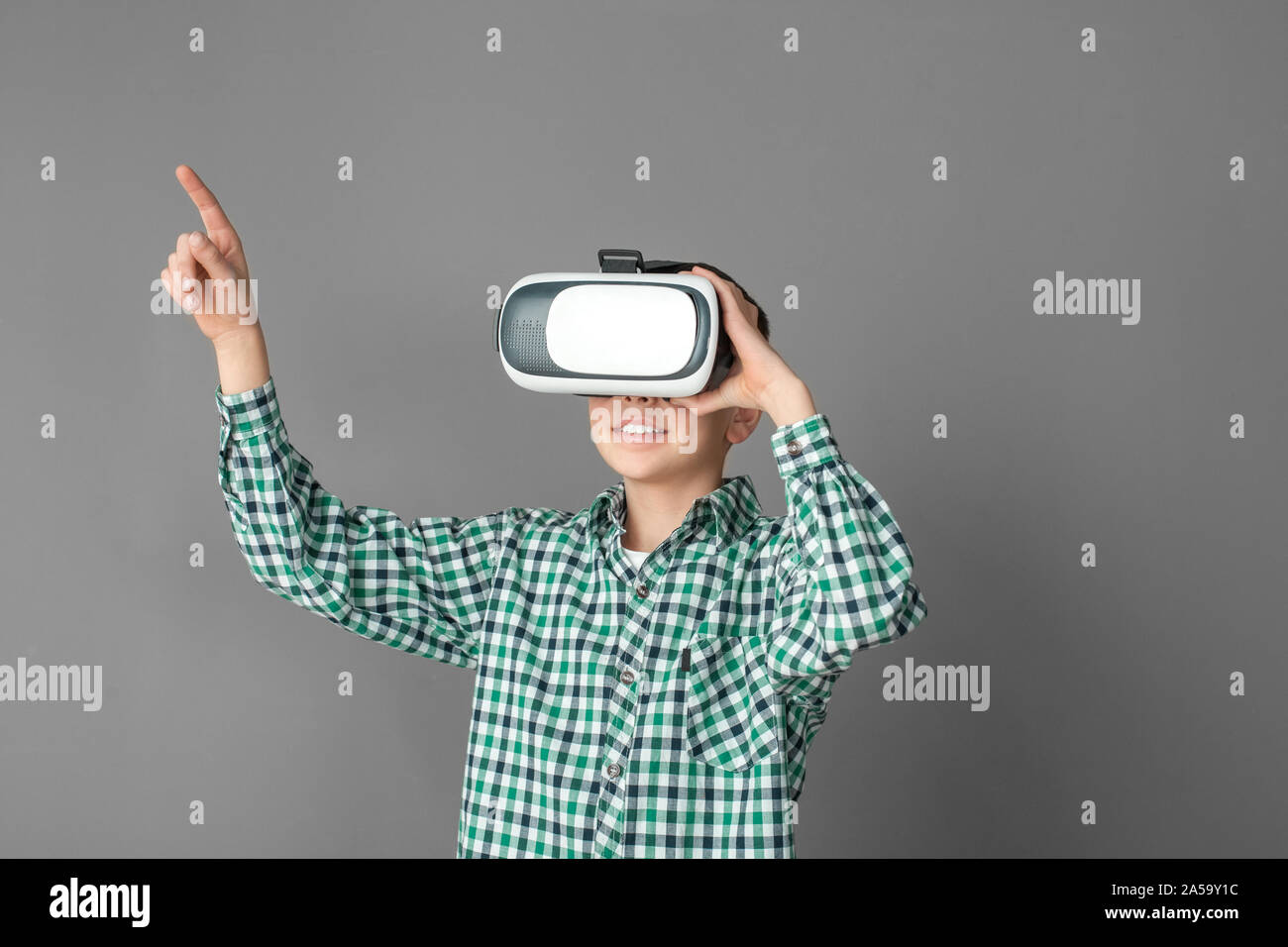 Freestyle. Boy in virtual reality headset standing isolated on grey ...