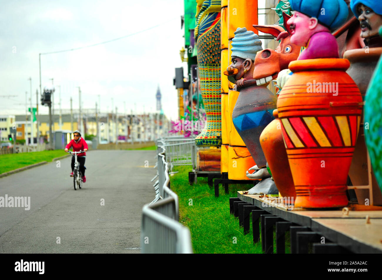 Lone female cyclist in a red top passing the Blackpool illuminations ...