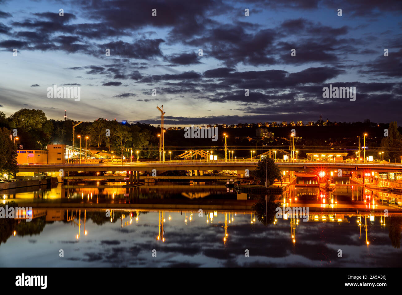 Germany, Glassy neckar river water reflecting illuminated train bridge ...