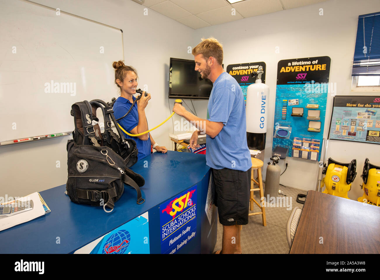 A SCUBA diving instructor explains a regulator to a student in a ...