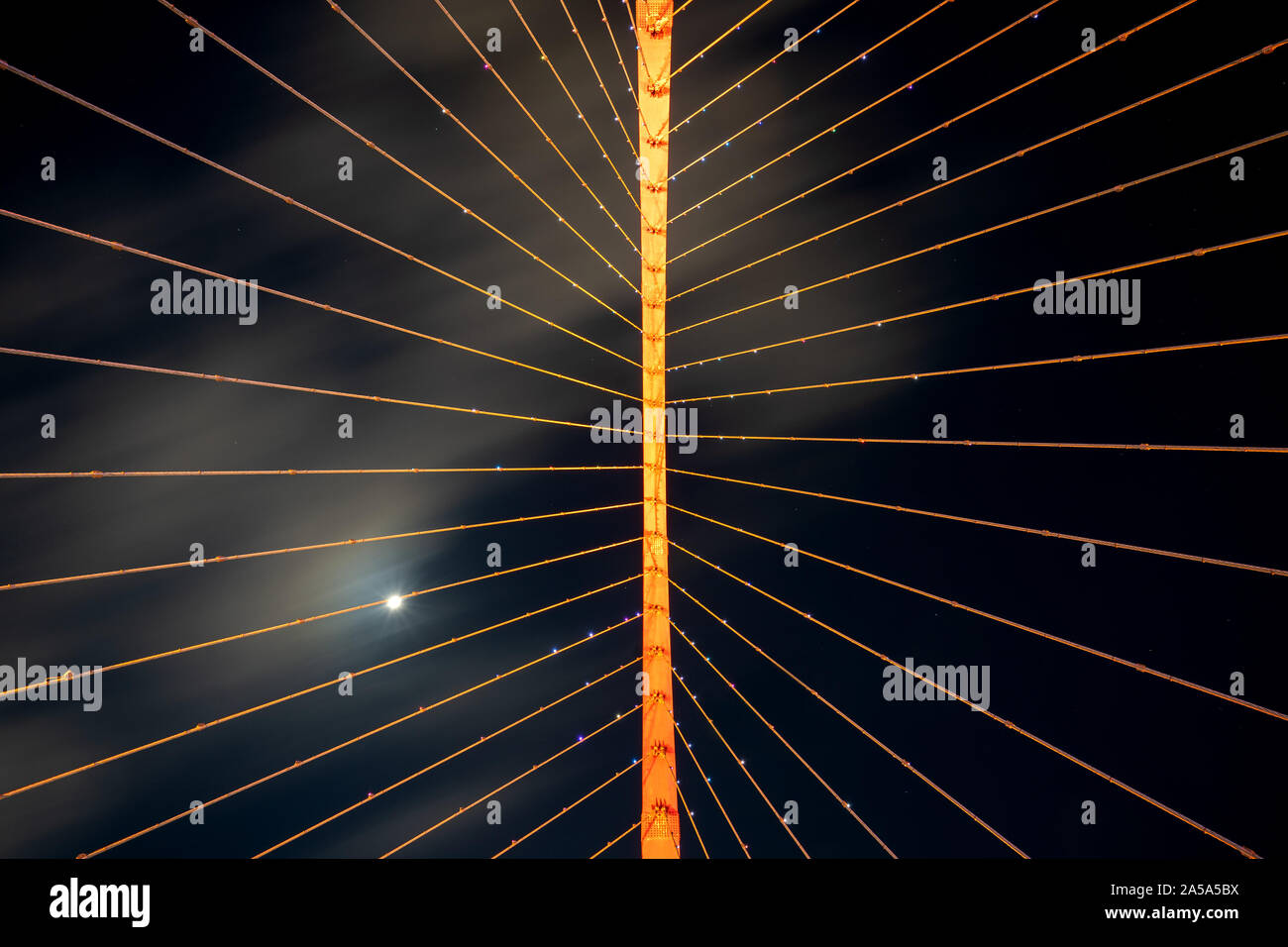 An abstract view upwards during night reveals the cabling of a ...