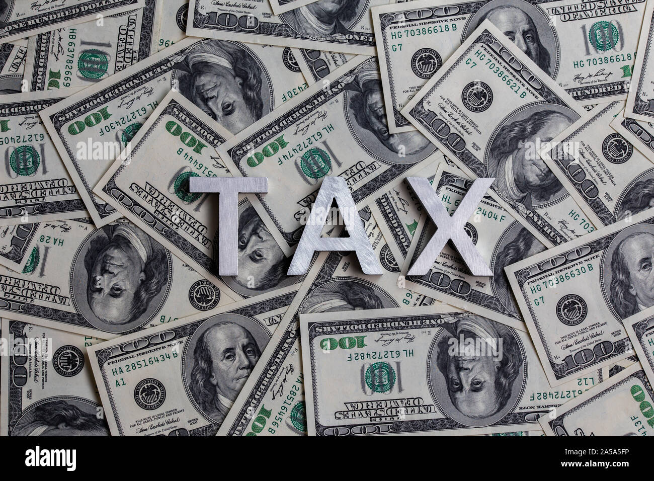 The words TAX laid with metal letters on the US dollar bills background ...