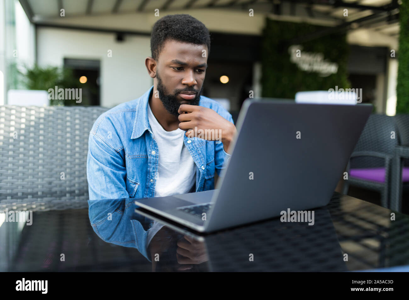 Young black man with laptop outside a cafe looking to camera Stock ...