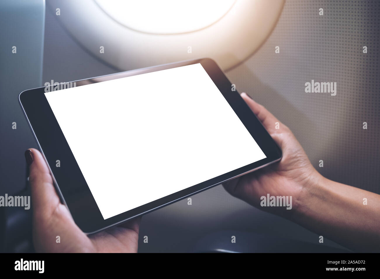 Mockup image of a woman holding and looking at black tablet pc with ...