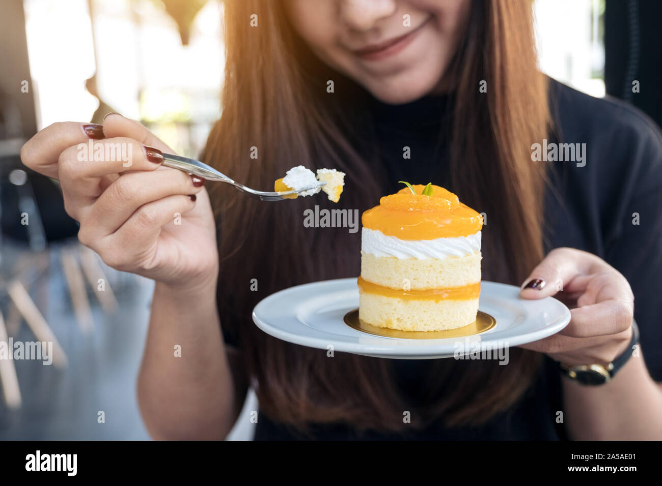 Closeup image of a beautiful Asian woman holding and eating an orange ...