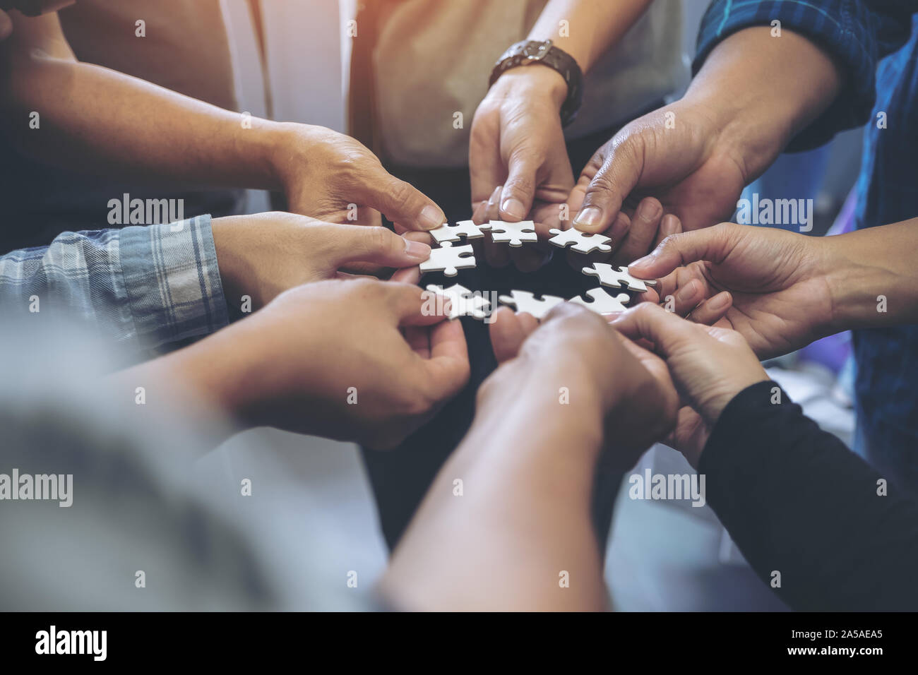 Closeup image of many people hands holding a jigsaw puzzle in circle ...