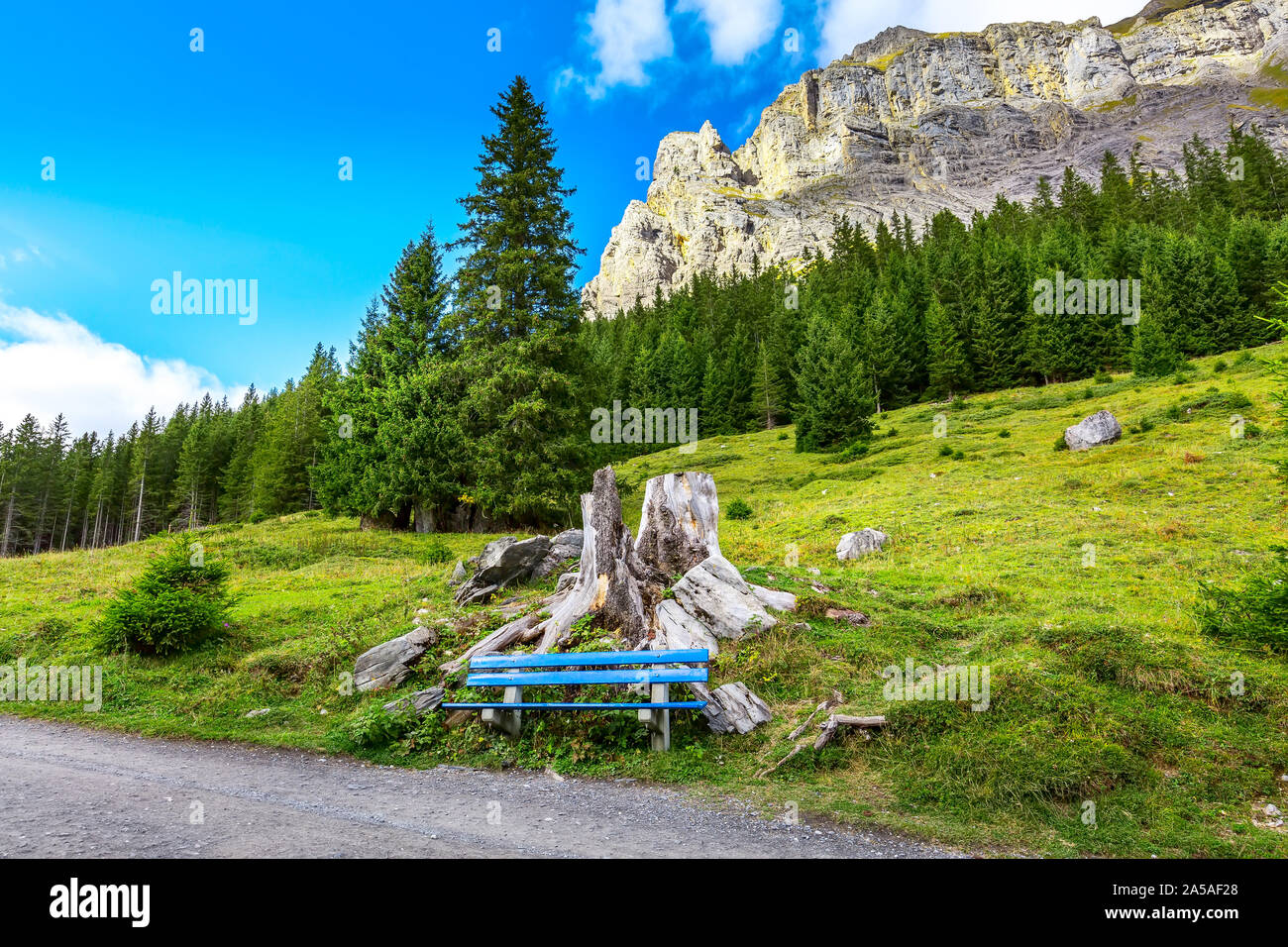 Blue bench on the pathway to Oeschinnensee lake and Swiss Alps panorama ...