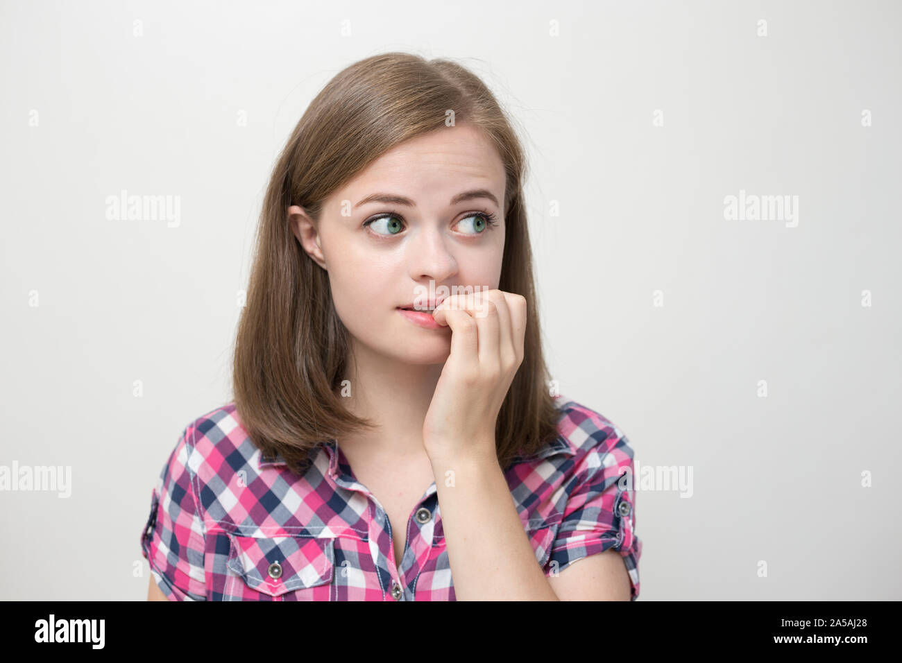 Young caucasian woman girl biting her nails, looking nervous or anxious ...