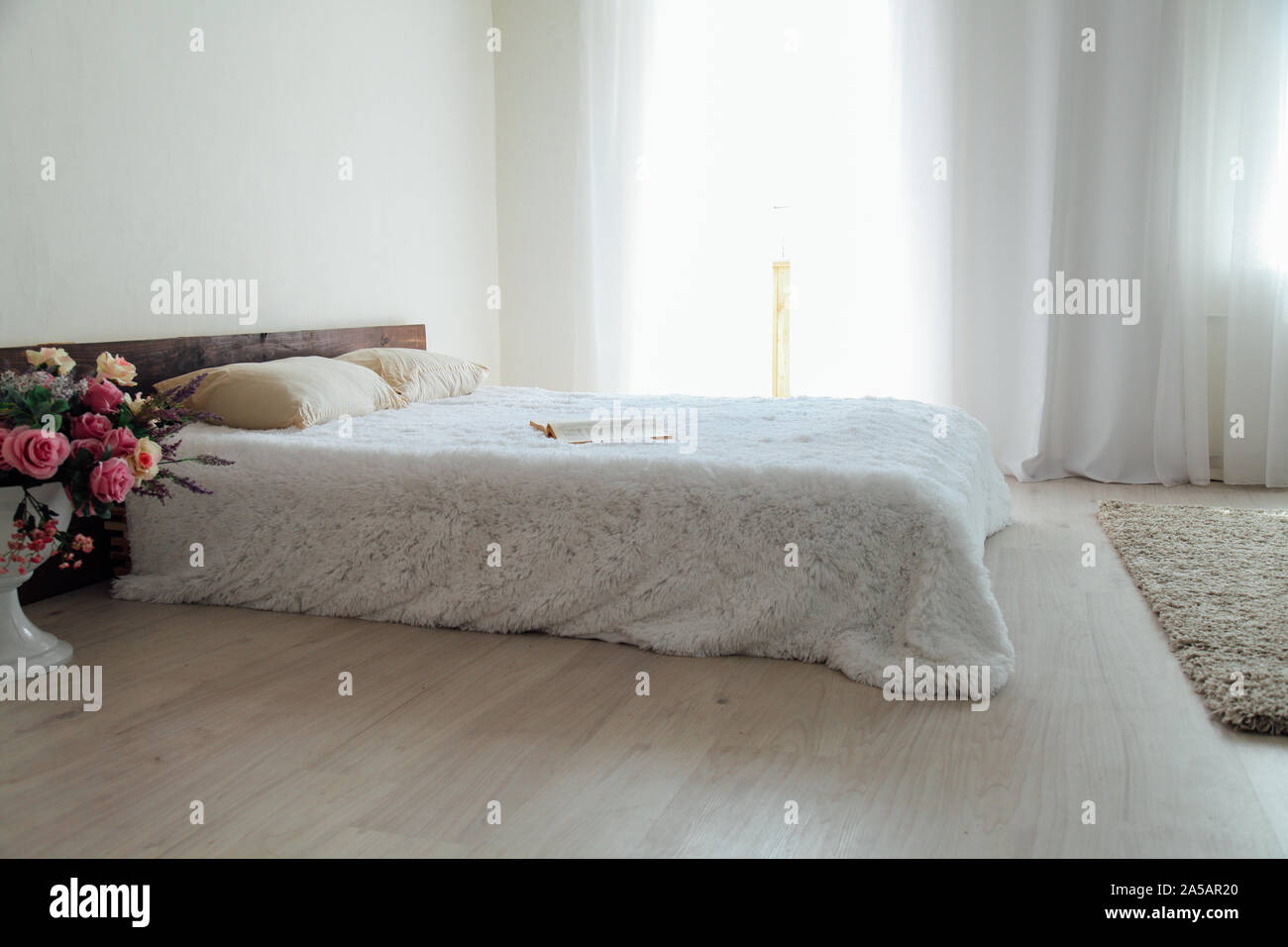 White bedroom bright interiors with bed and flowers Stock Photo - Alamy