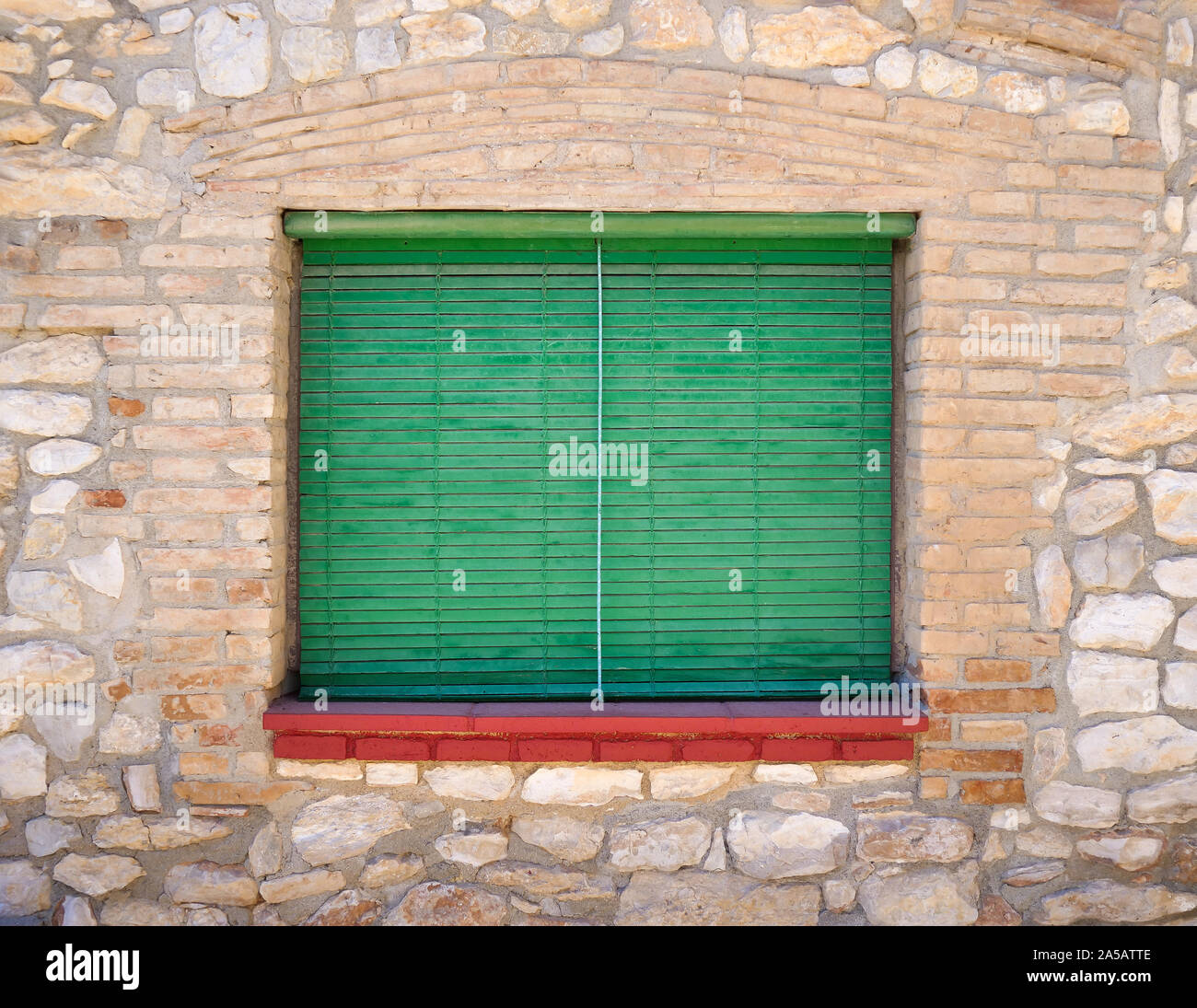 Window with wooden green shutters and a red windowsill in an old stone ...